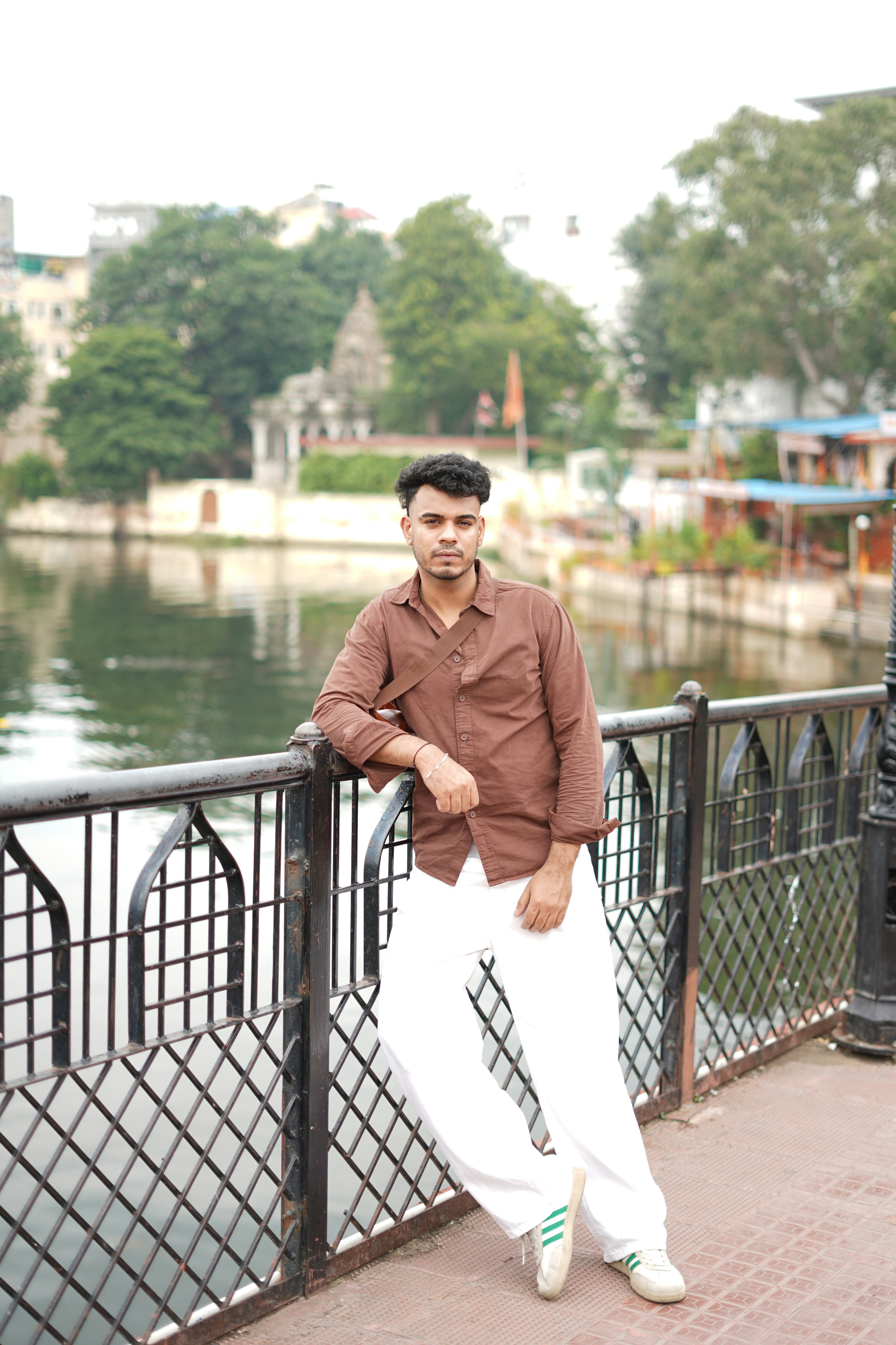 Young man leaning on a railing by a lake.