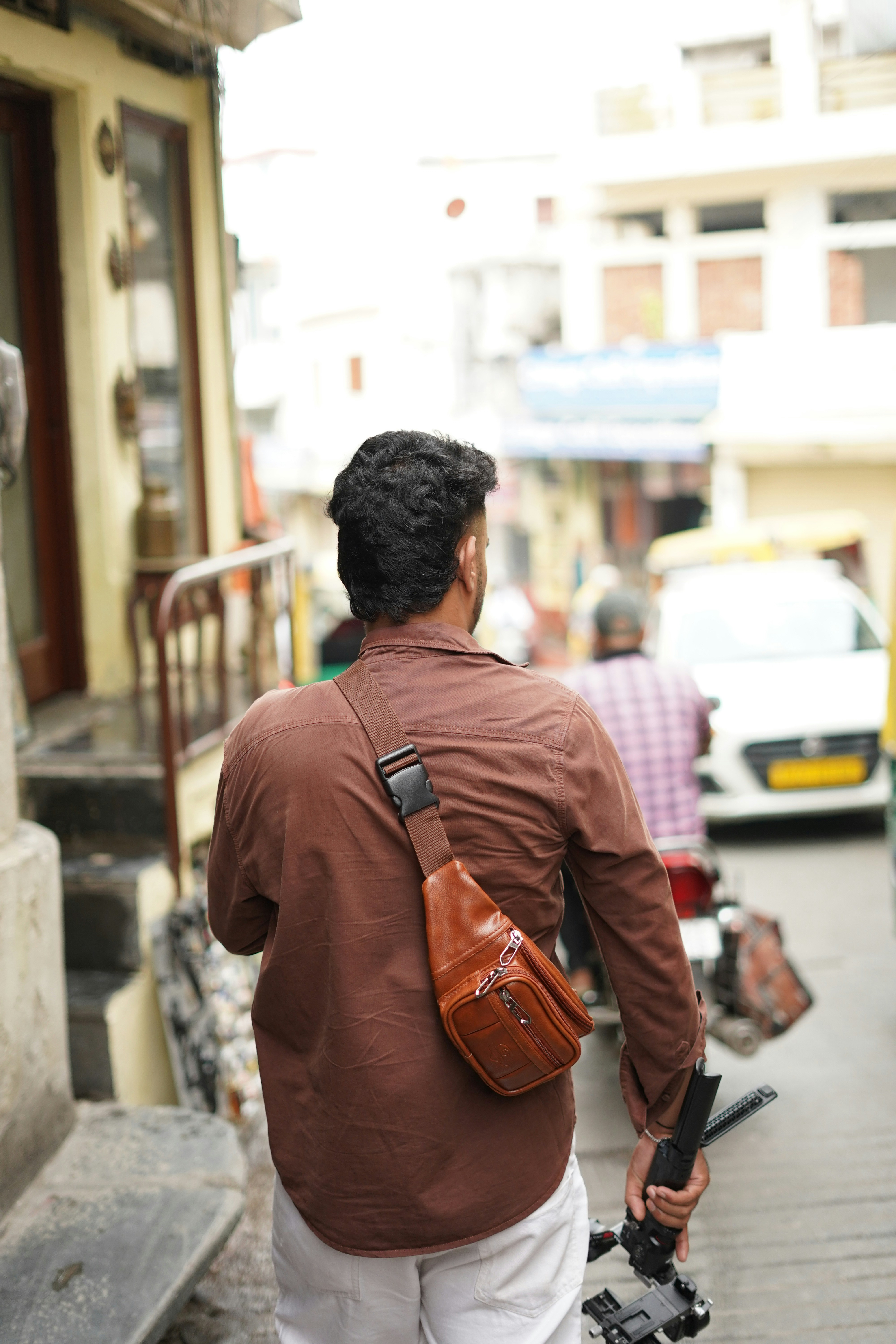 Man with fanny pack walks down narrow street