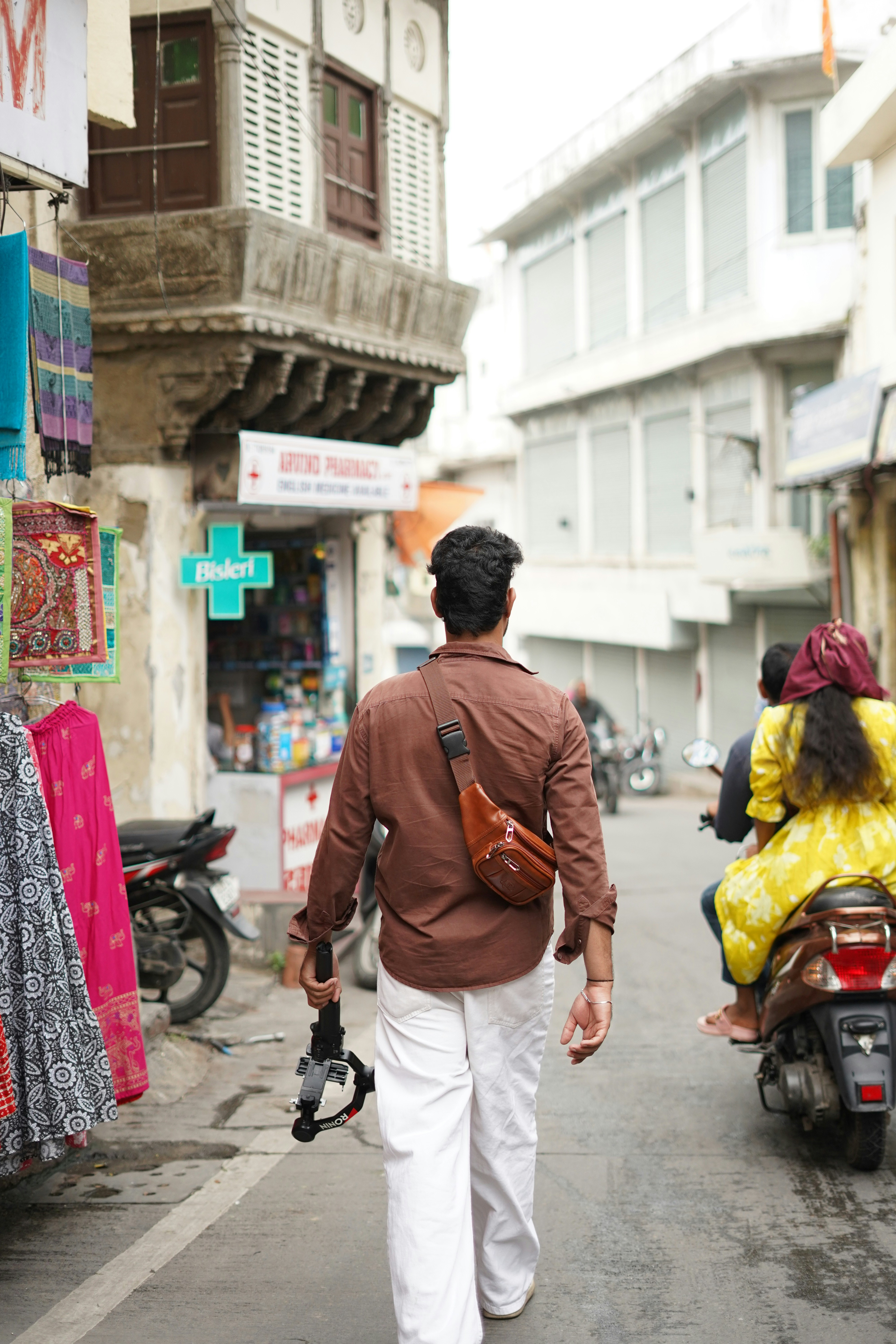 Man walking down a street with a pharmacy.