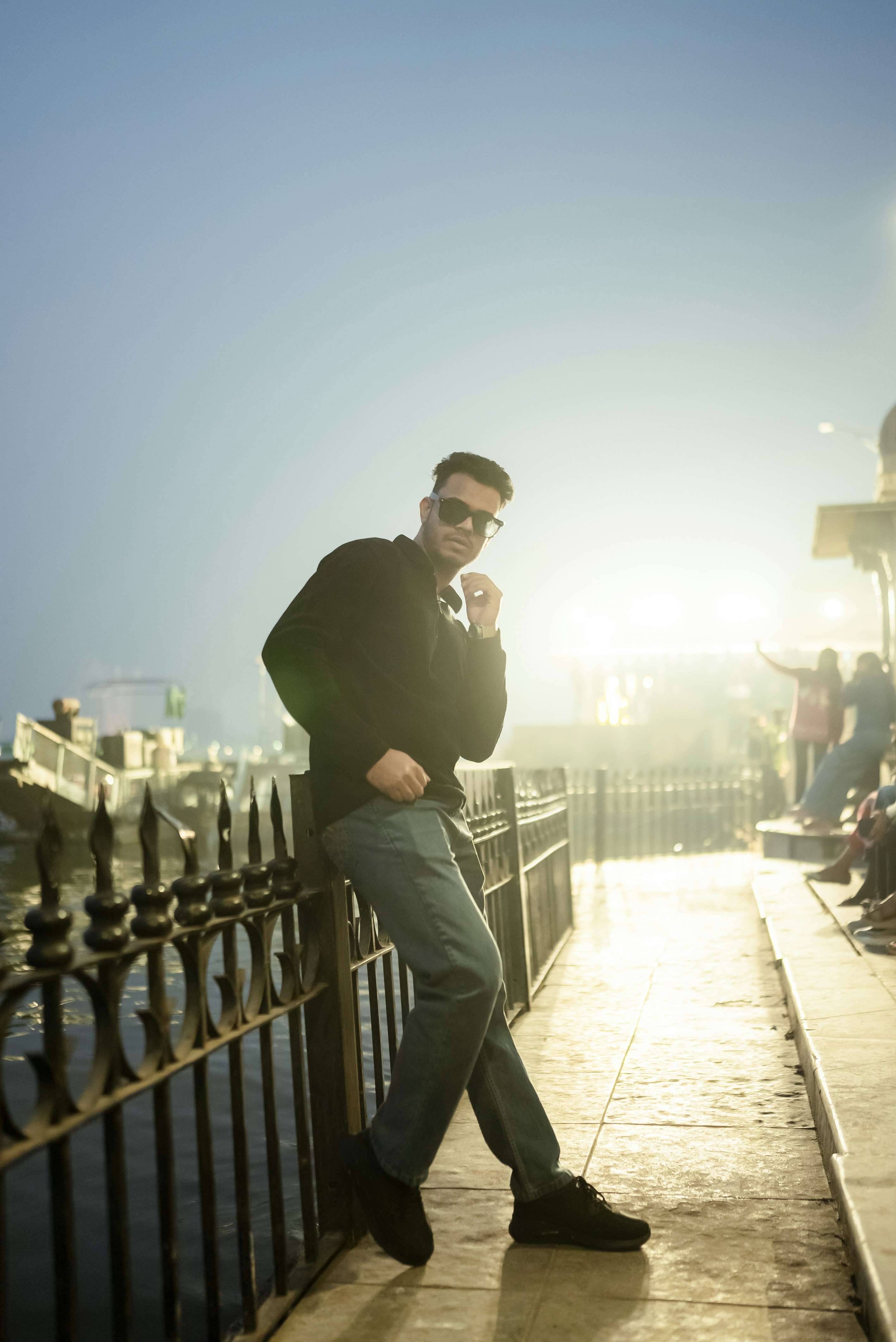 Man leaning on a railing outdoors at dusk