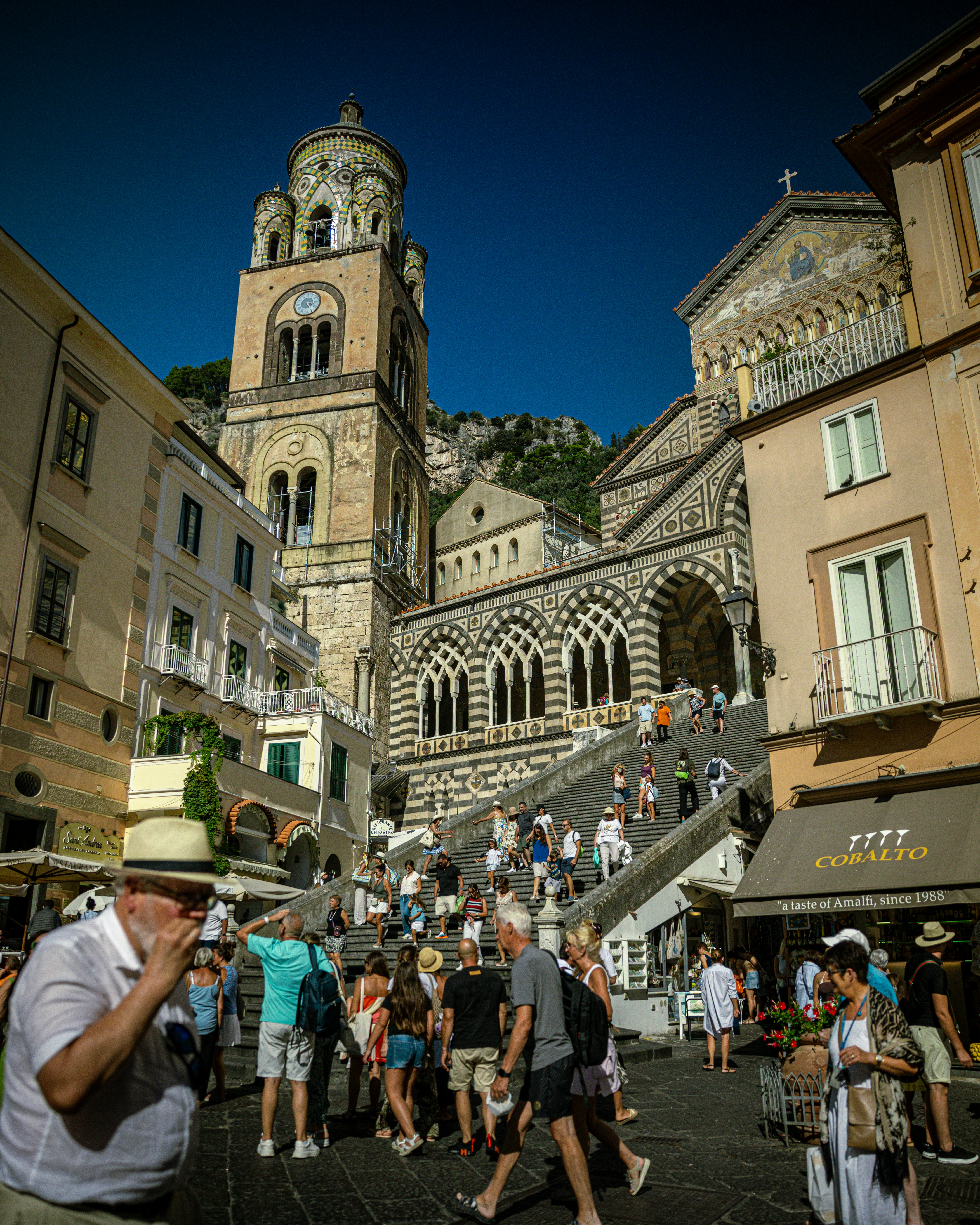 Staircase under striped arches: crowds ascend toward Amalfi's cathedral facade