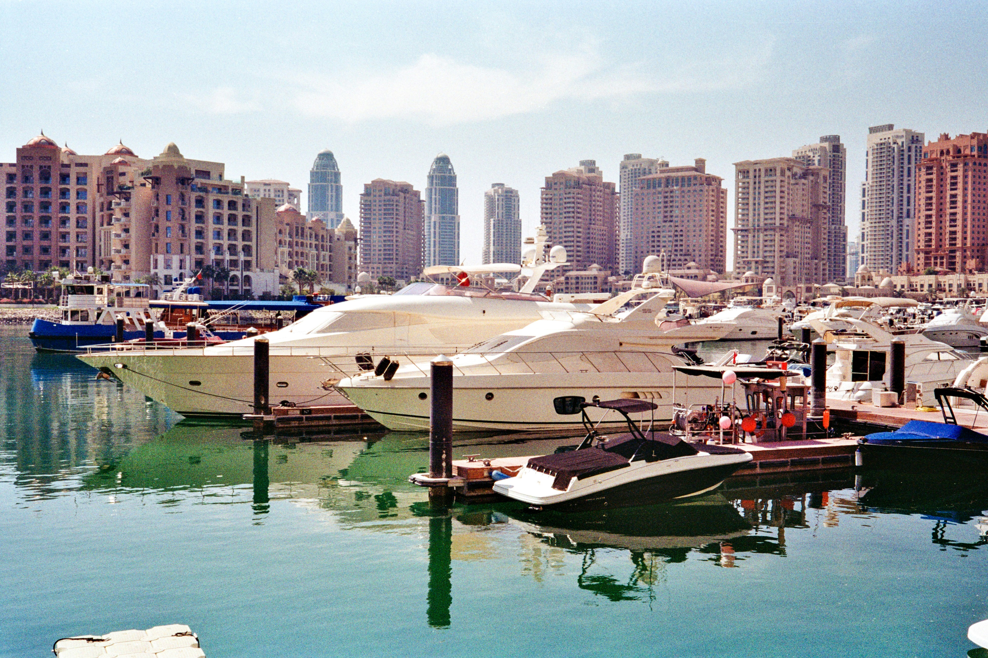 Kodak Gold 200 🎞️ | Luxury yachts docked in a modern harbor with city skyline.