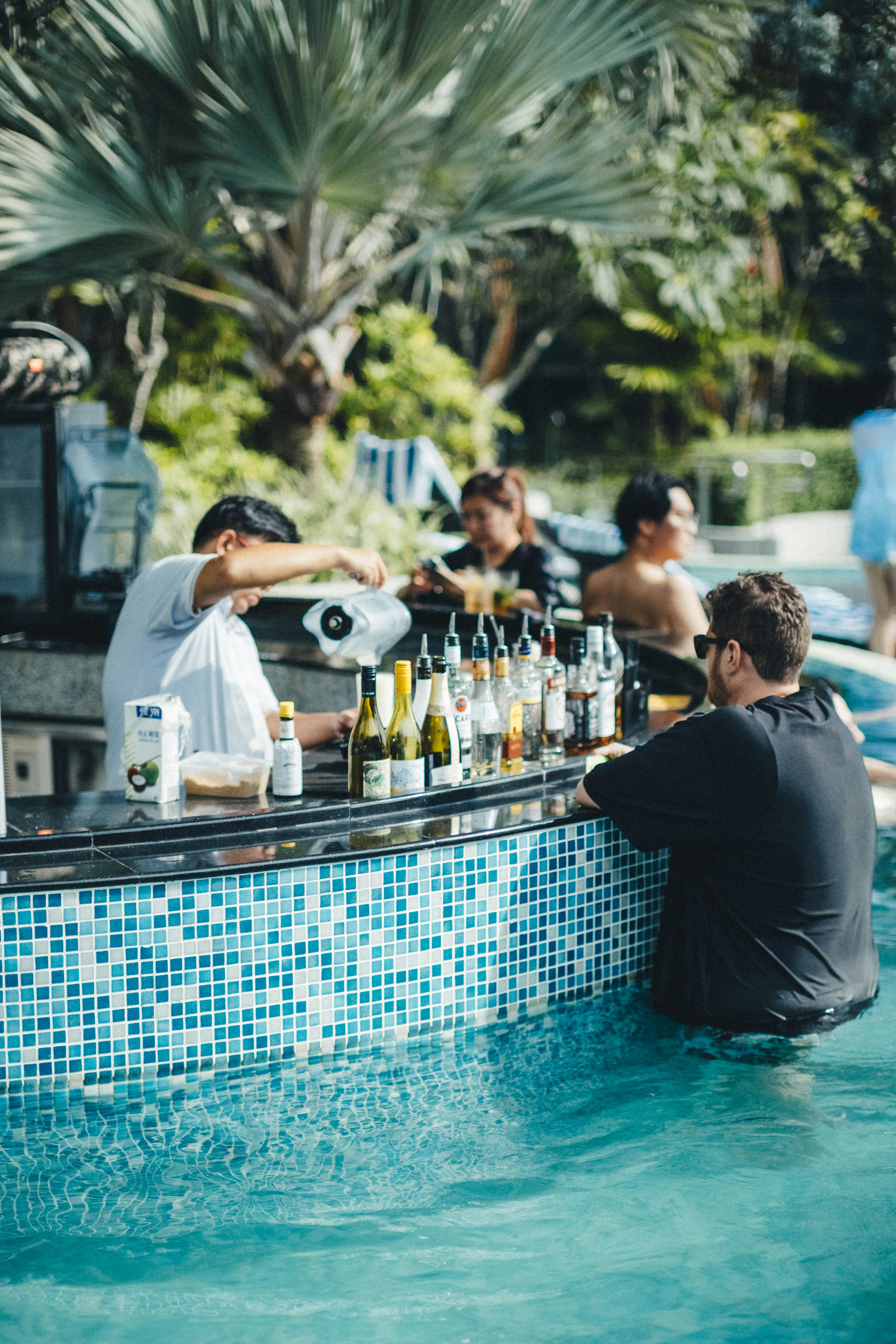 People at a poolside bar with bottles of alcohol.