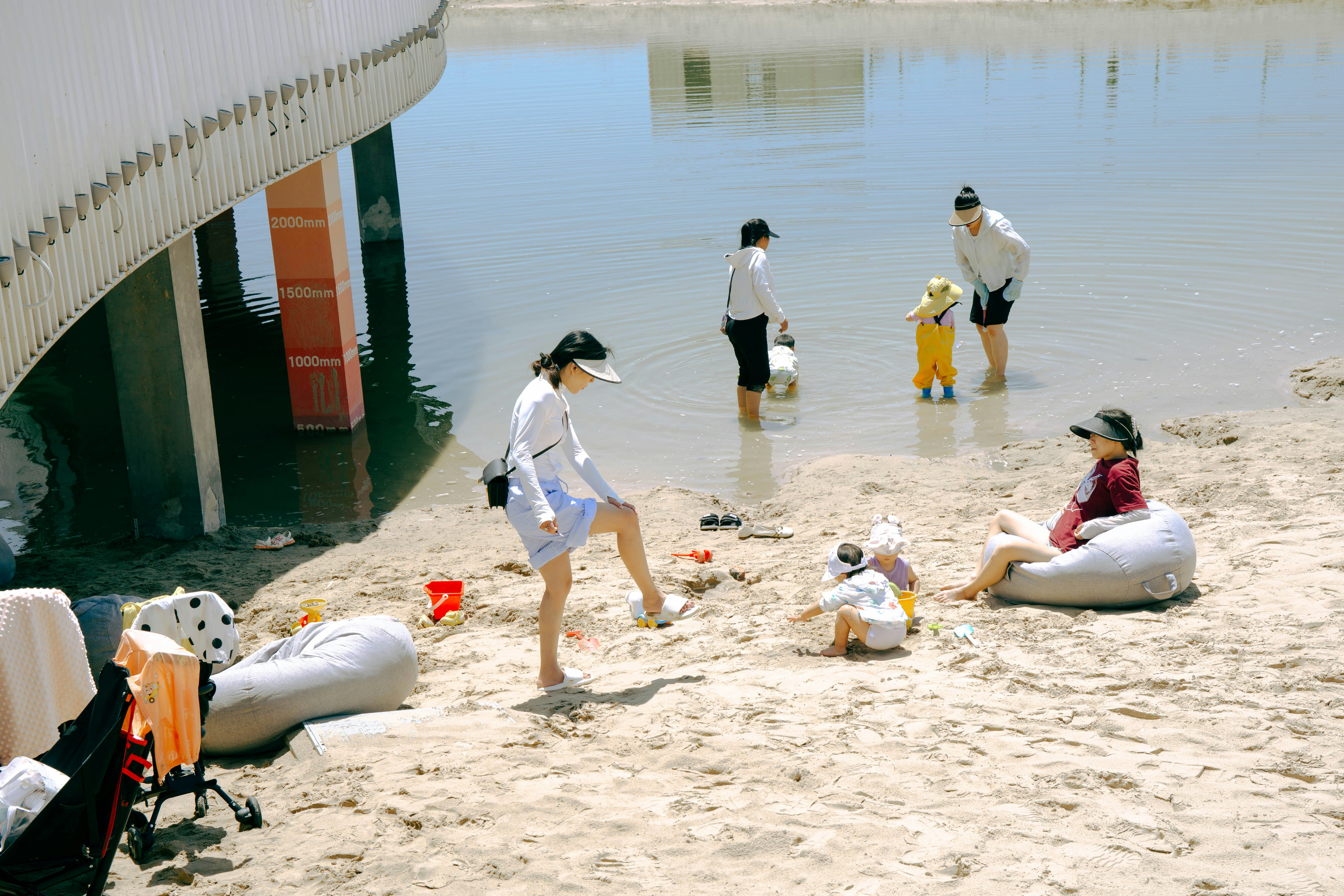 Sunny Day, Shallow Water | People relaxing on a sandy beach by the water.