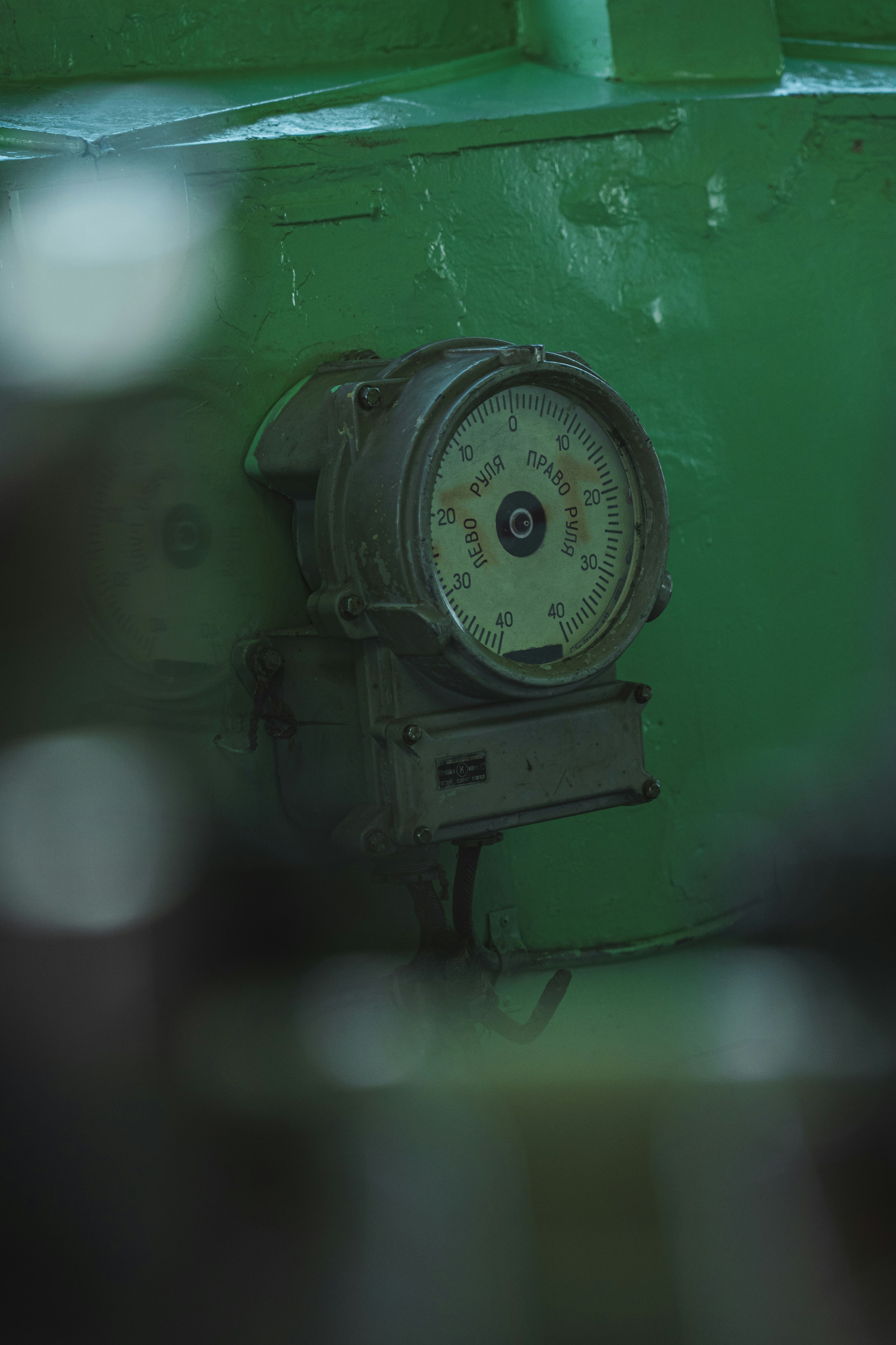 A vintage pressure gauge mounted on a green wall, showcasing a blend of industrial design and nostalgia.