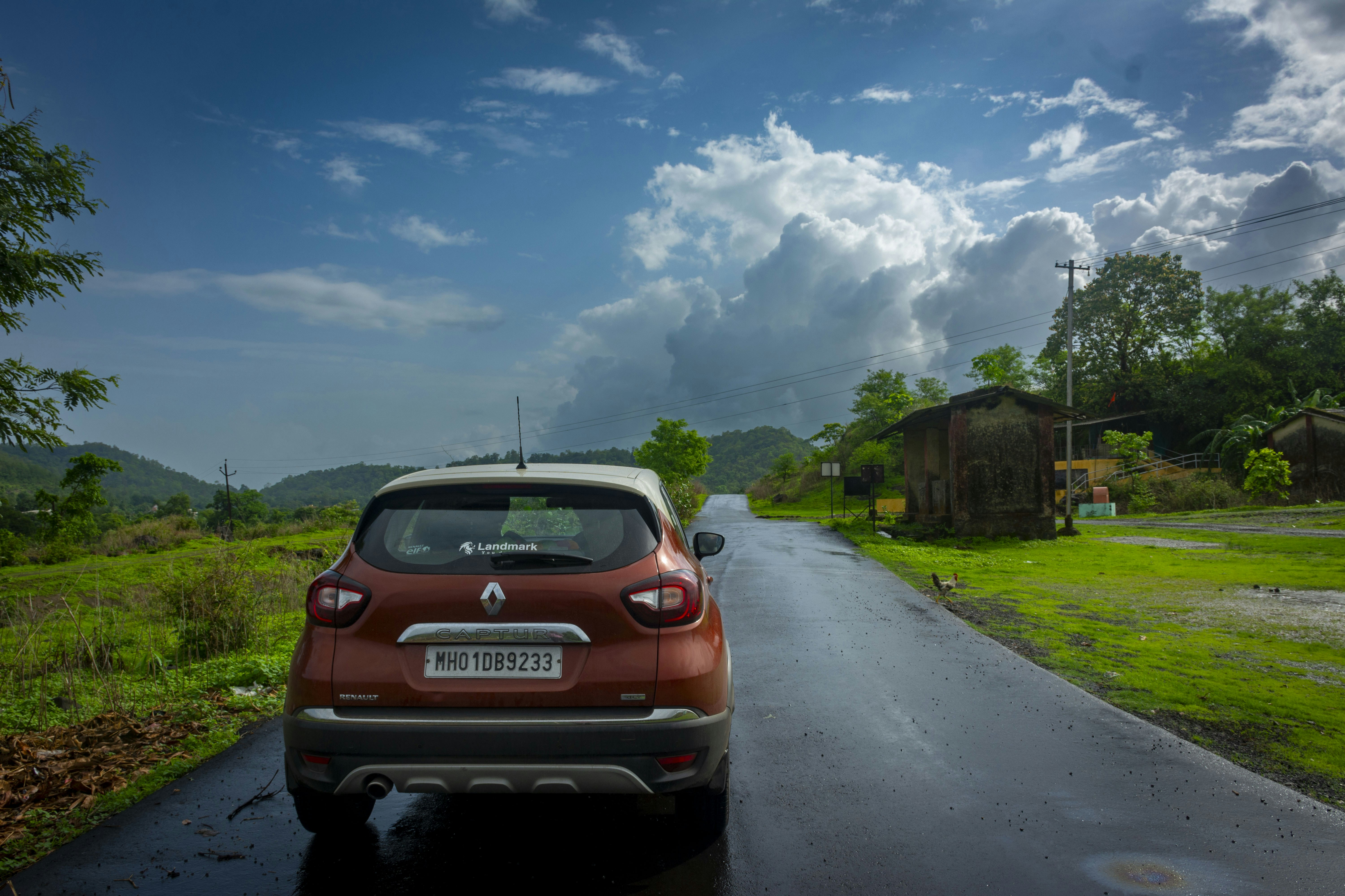 Red SUV on a Rainwashed Rural Road Beneath a Looming Cloudscape