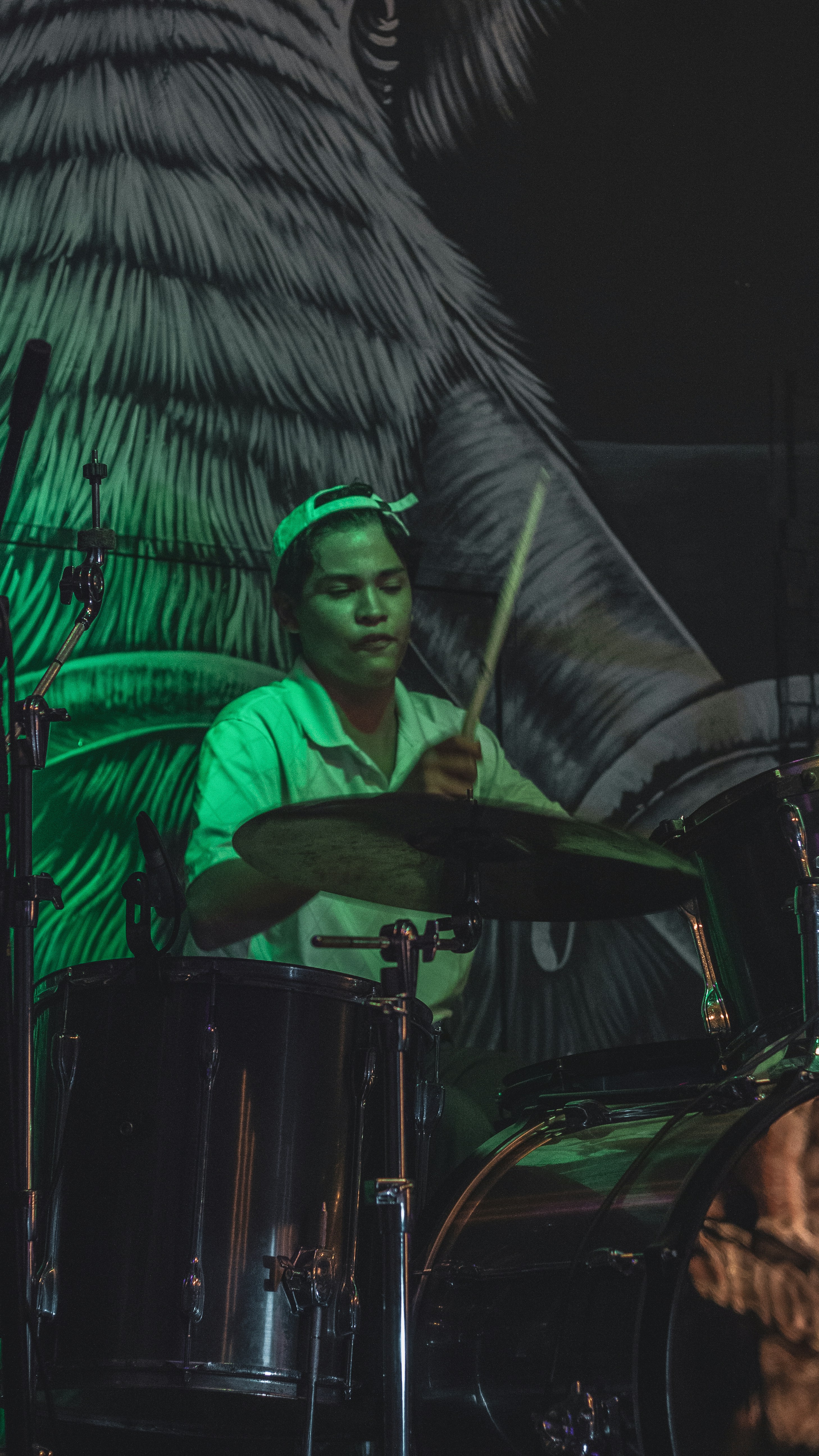 groove at center stage: drummer in green-lit ambience