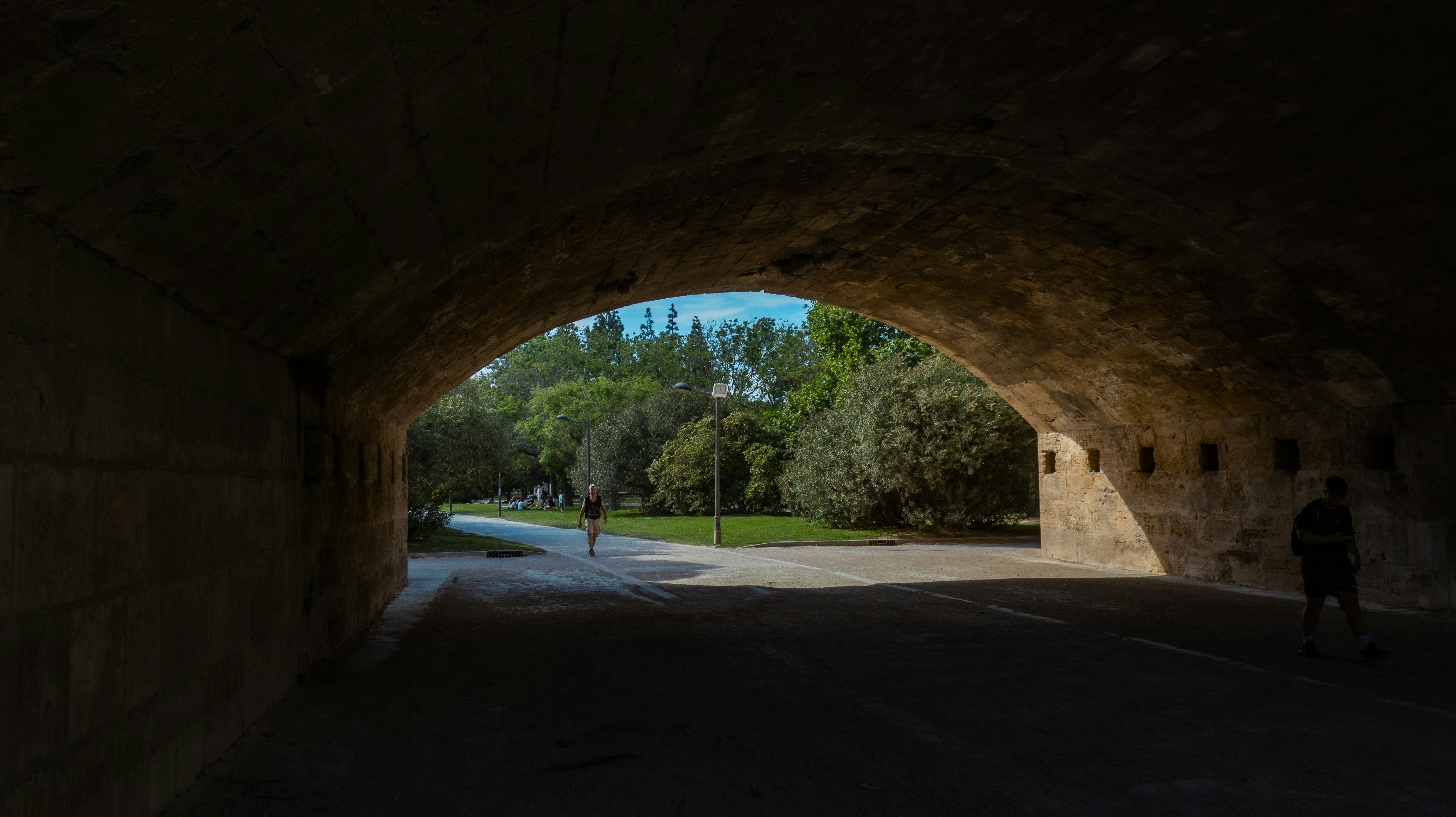 People walking through a tunnel towards a park