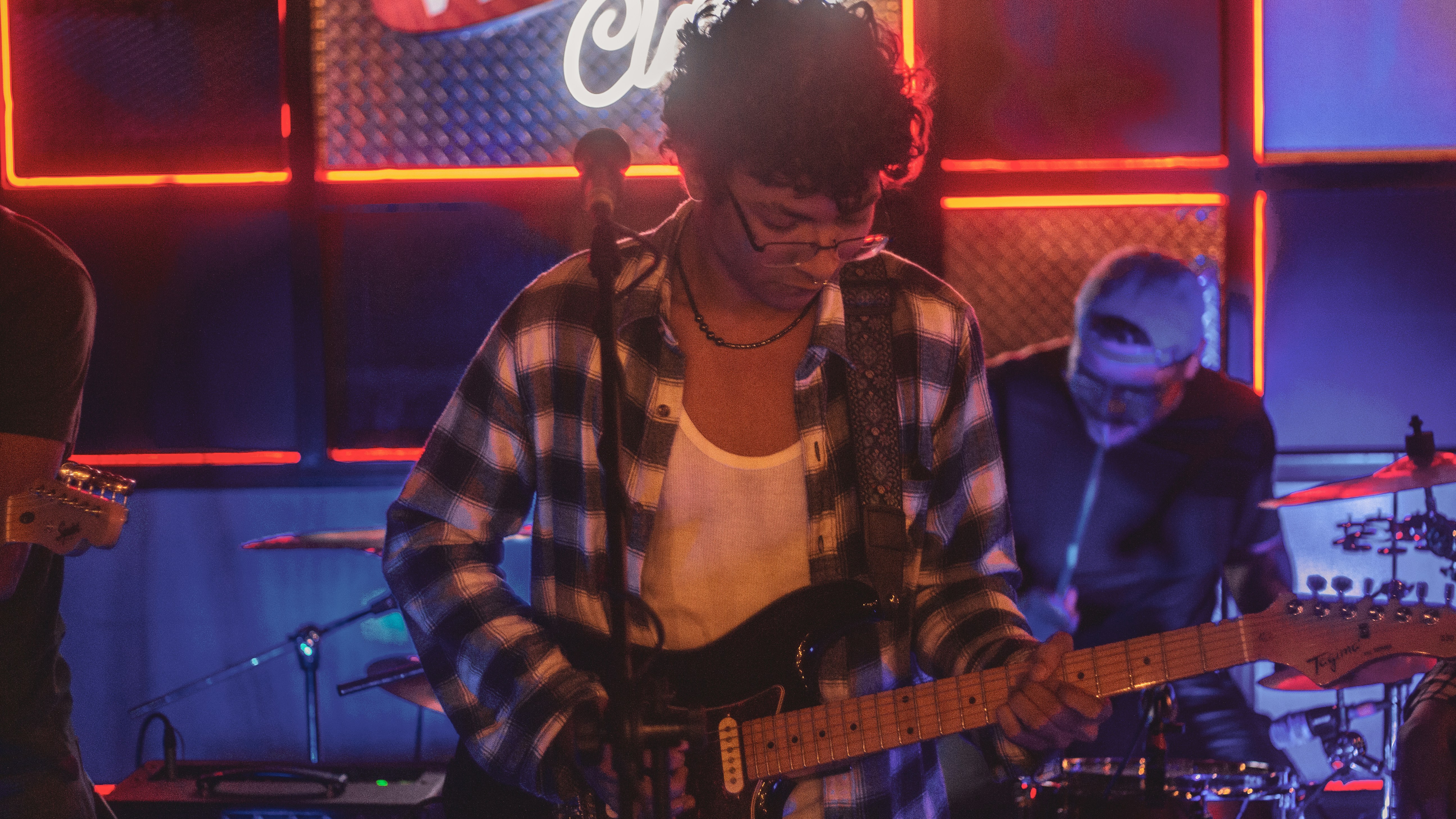 Crimson Neon Riff: A Plaid-Clad Guitarist Under Stage Lights