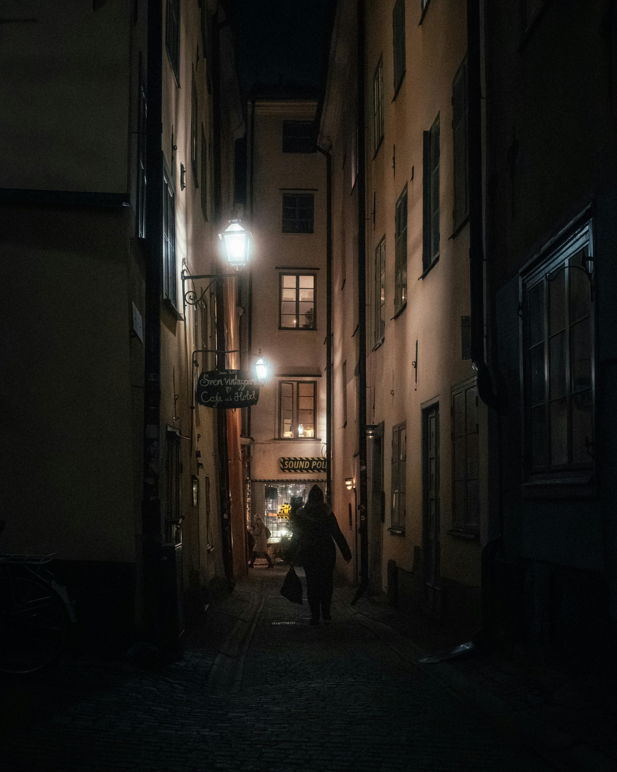 Instagram: @withdanial | Person walking down a dimly lit narrow street at night.