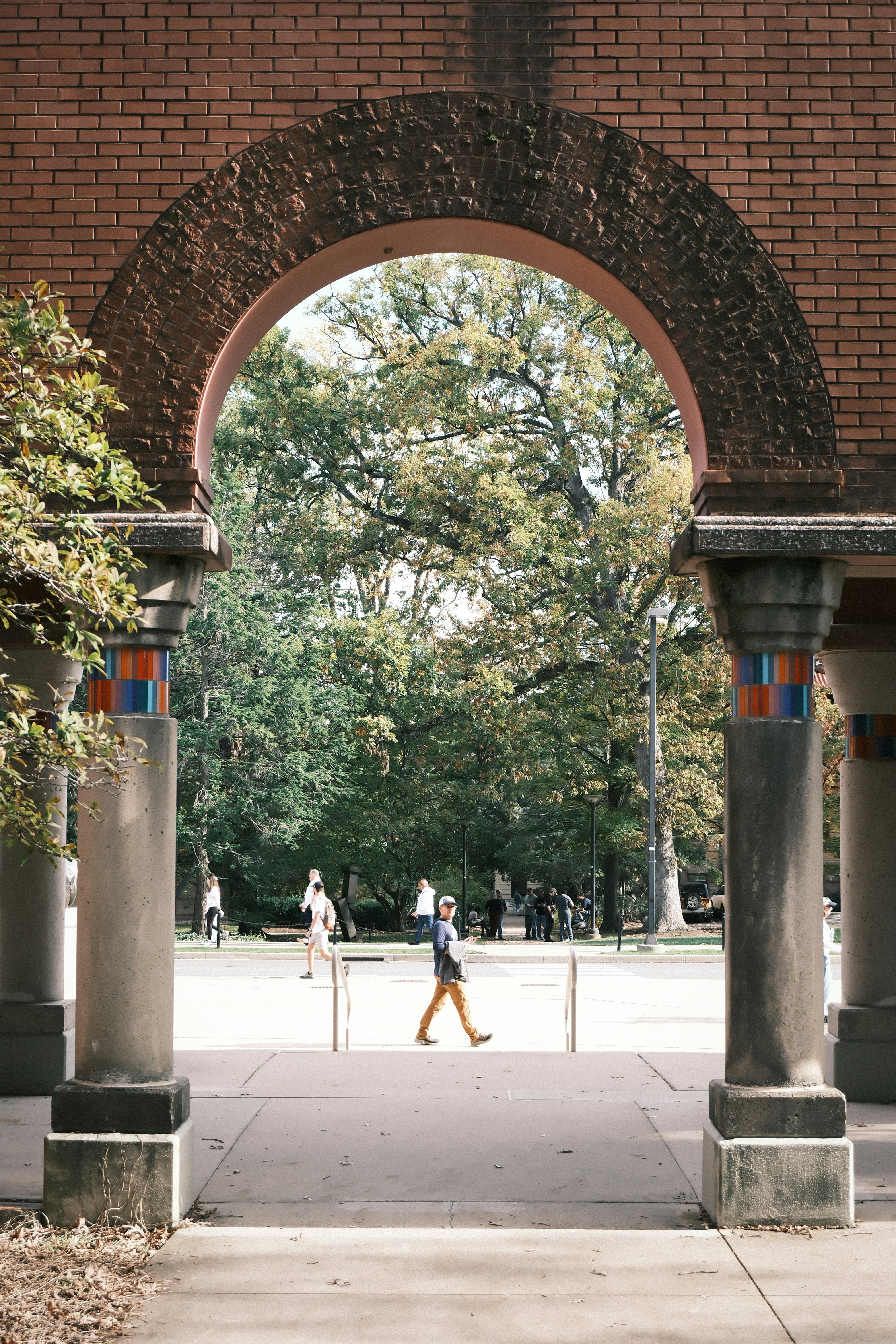 Man walks through archway into park with trees