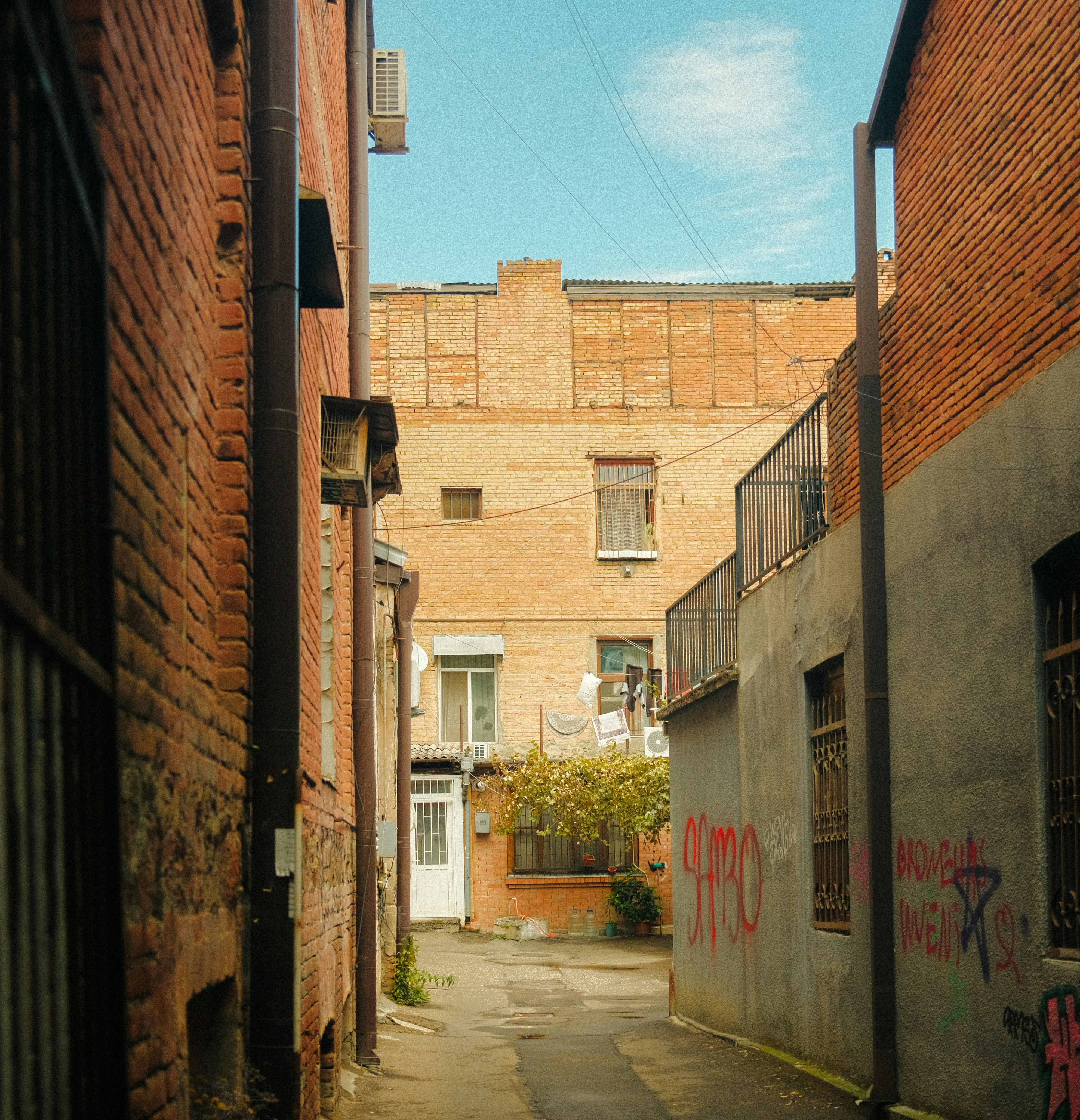 Tbilisi, September 2025. | Narrow alley between brick buildings under a blue sky