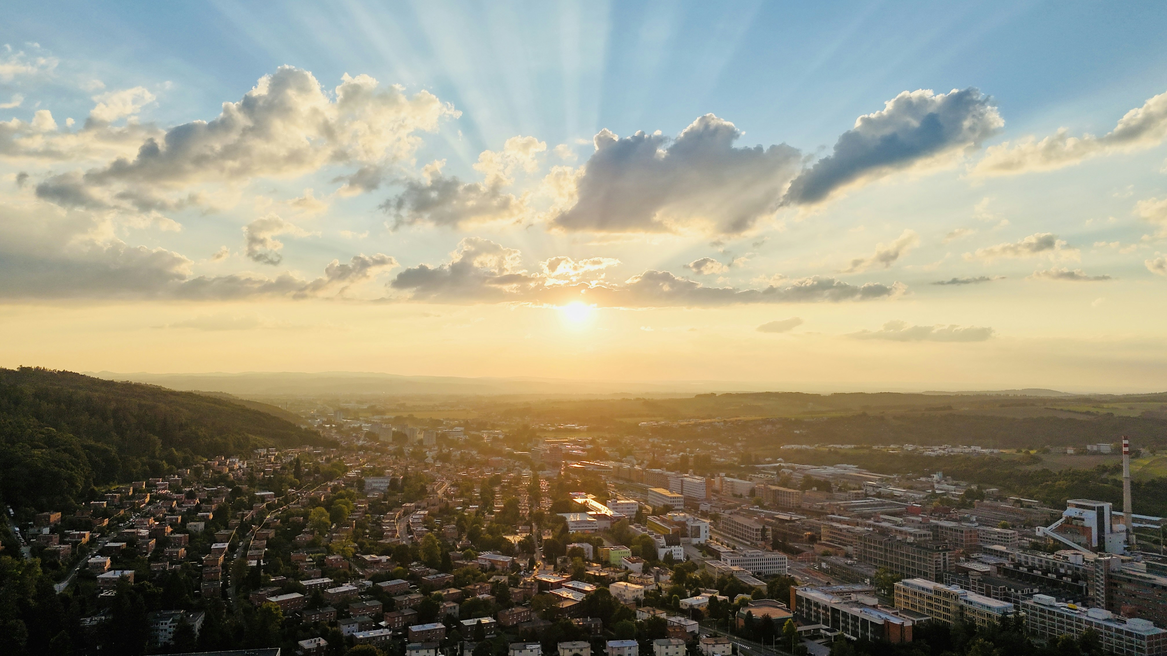 Zlín - západ slunce | Sunbeams shine over a city at sunset.