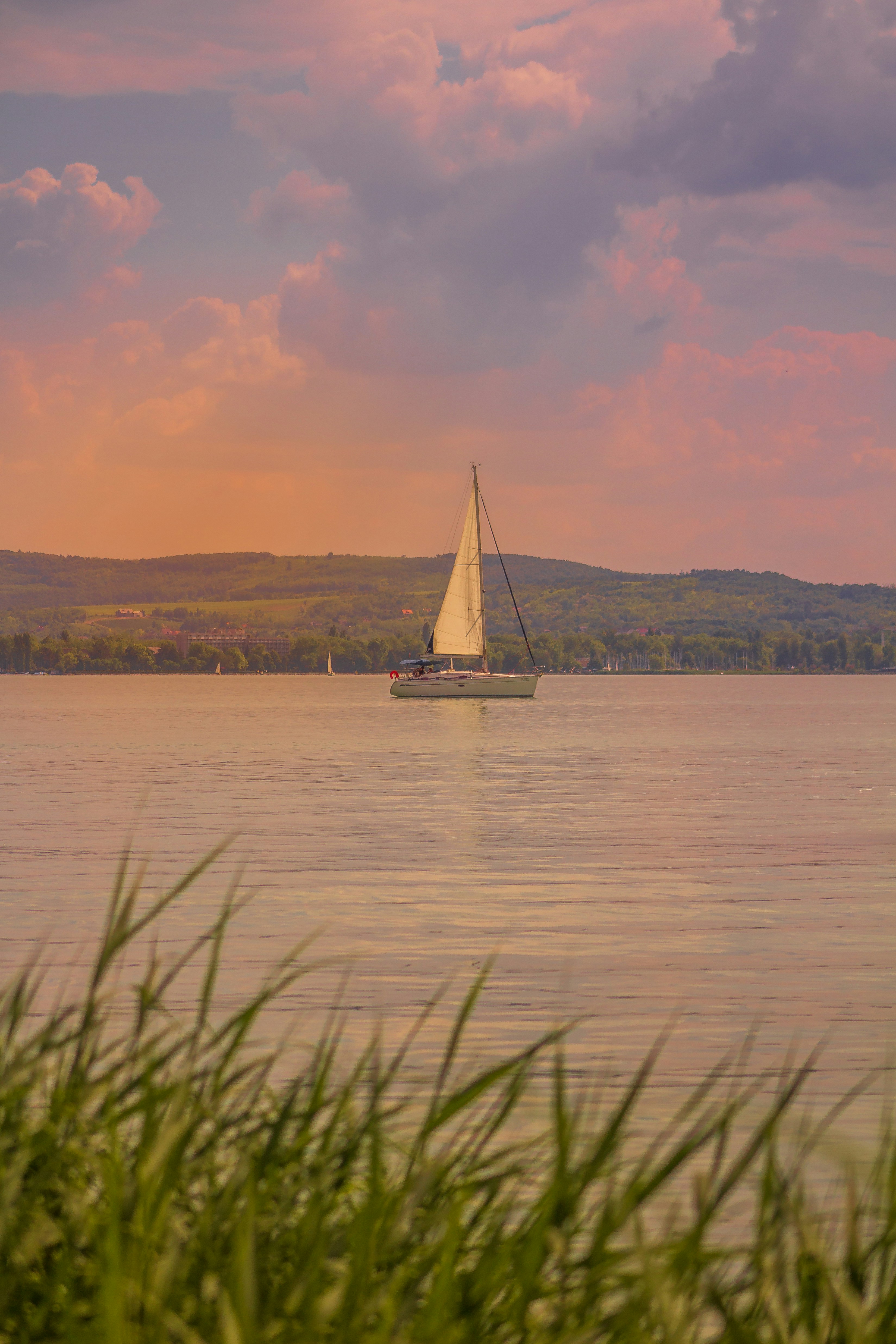 Sailboat at Golden Hour: A Quiet Lake Beneath Coral Clouds