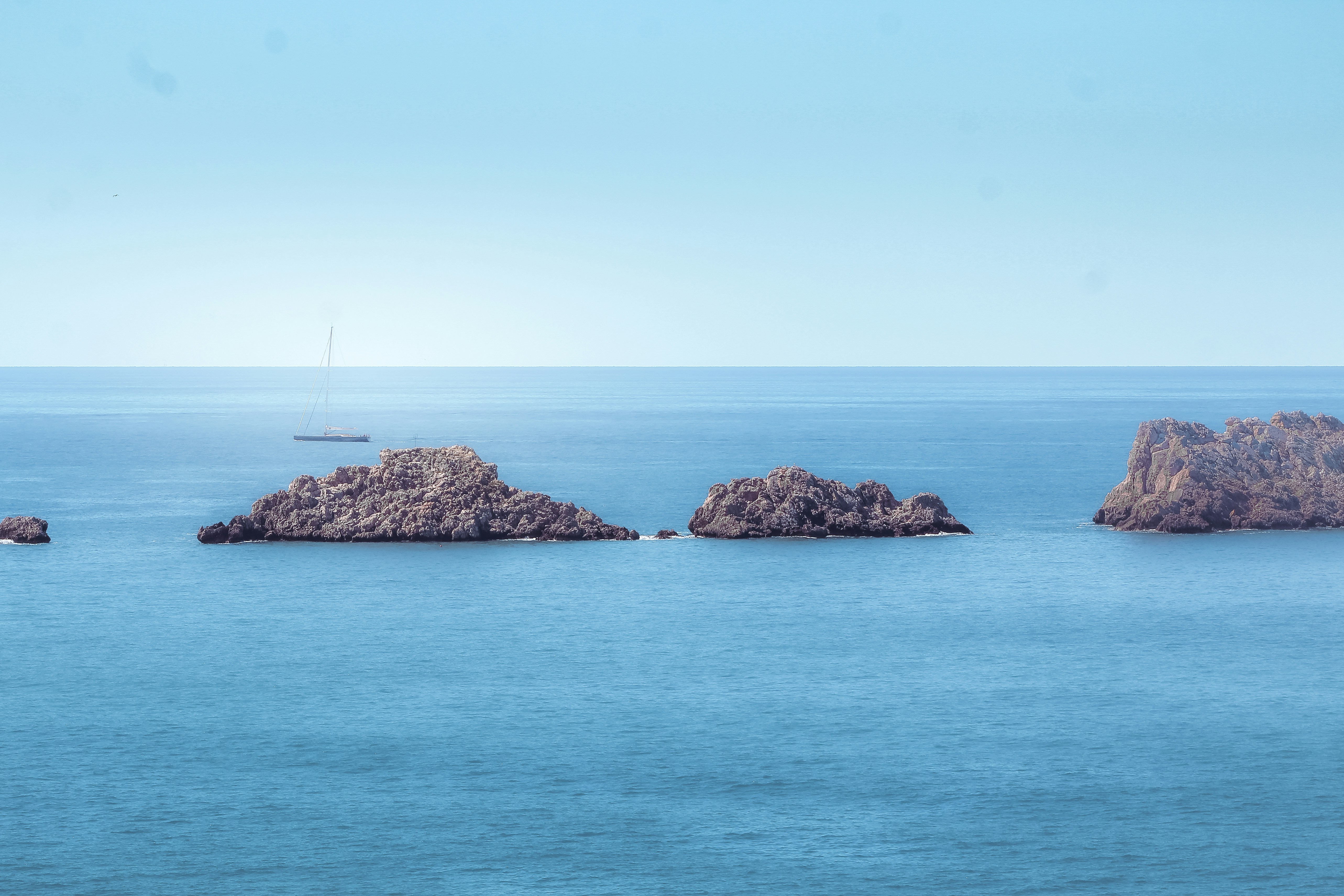 Rocky islands in a calm blue ocean under clear sky