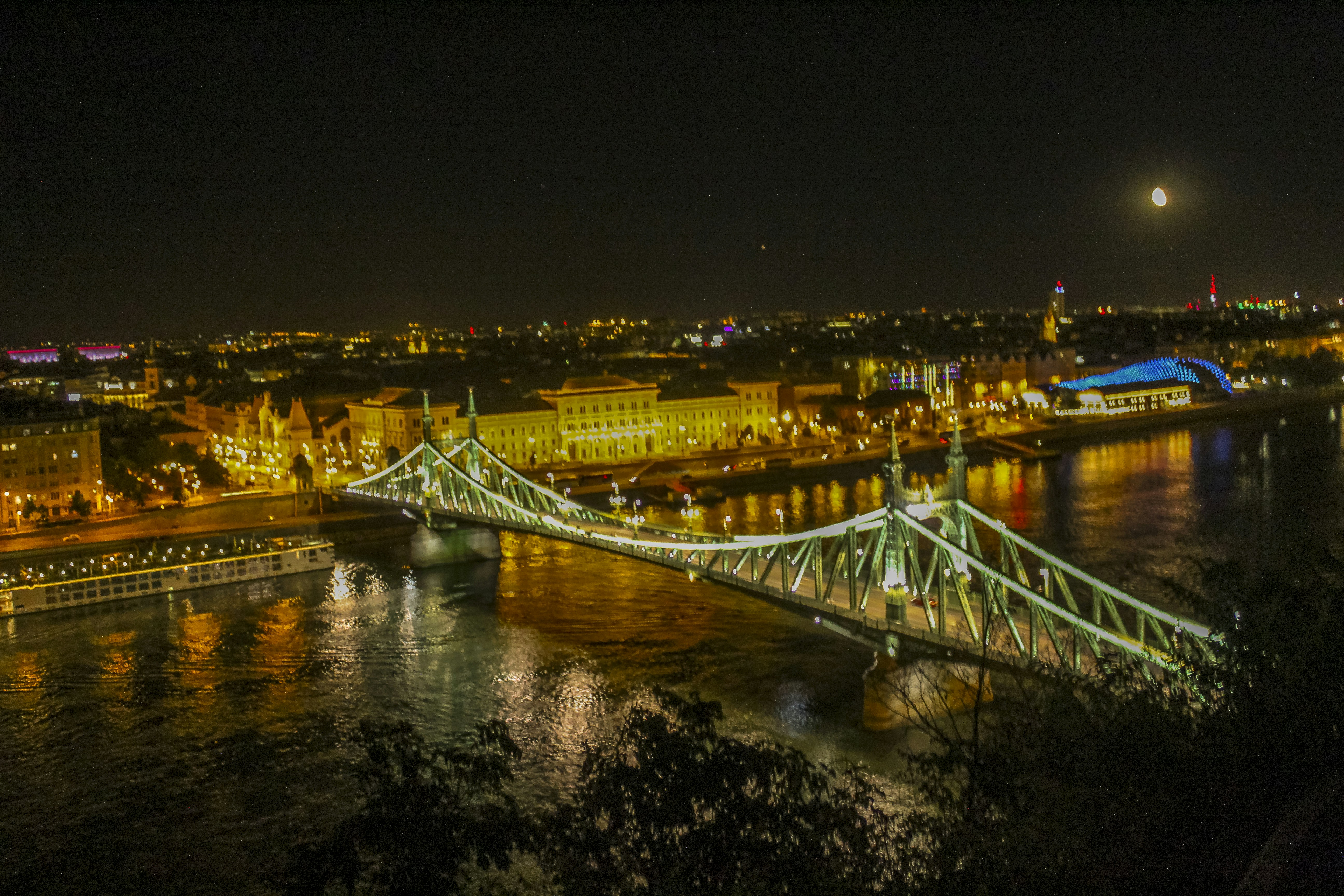 Green bridge illuminated at night over river
