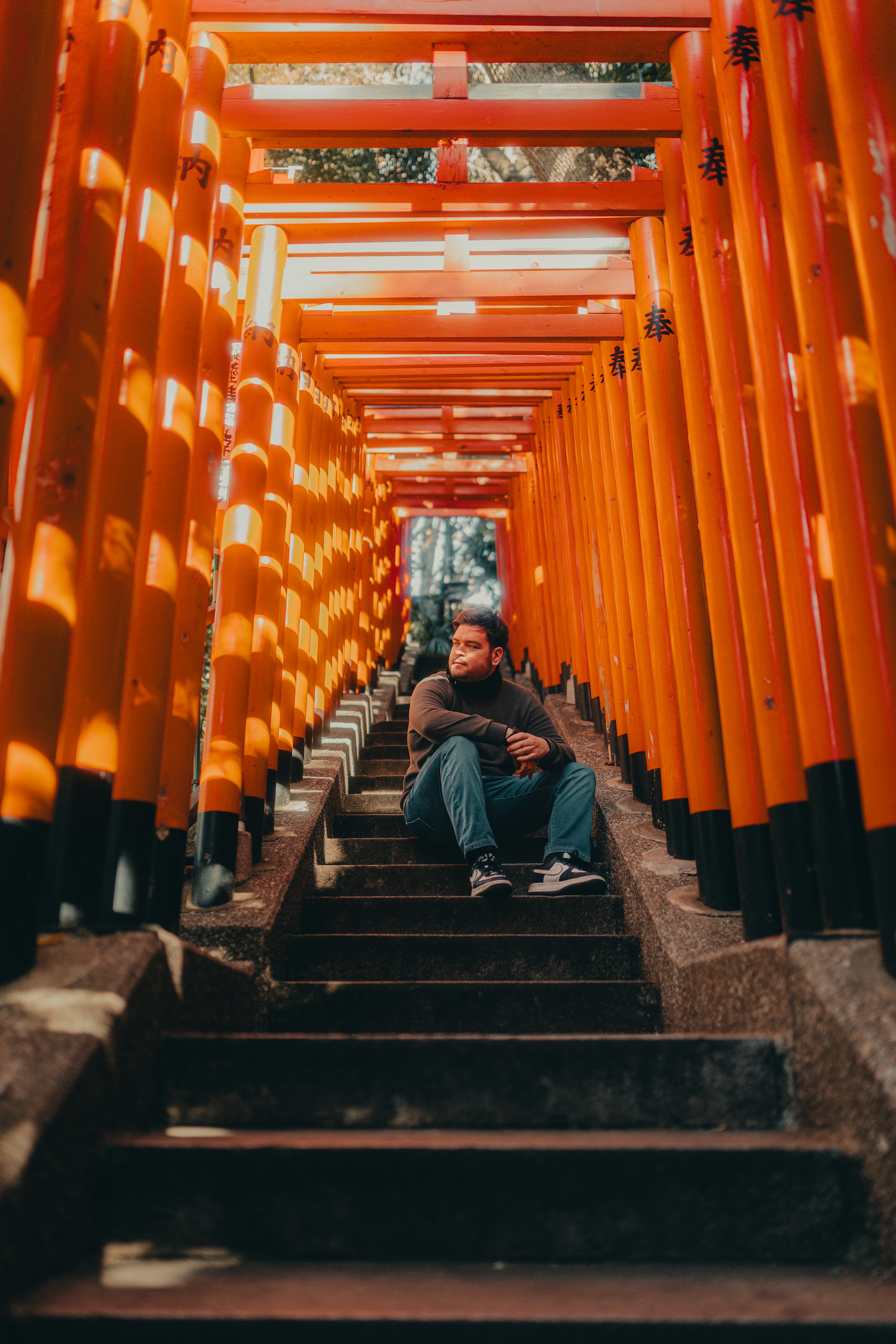 Ig @sir.simo | Man sitting on stairs between orange torii gates