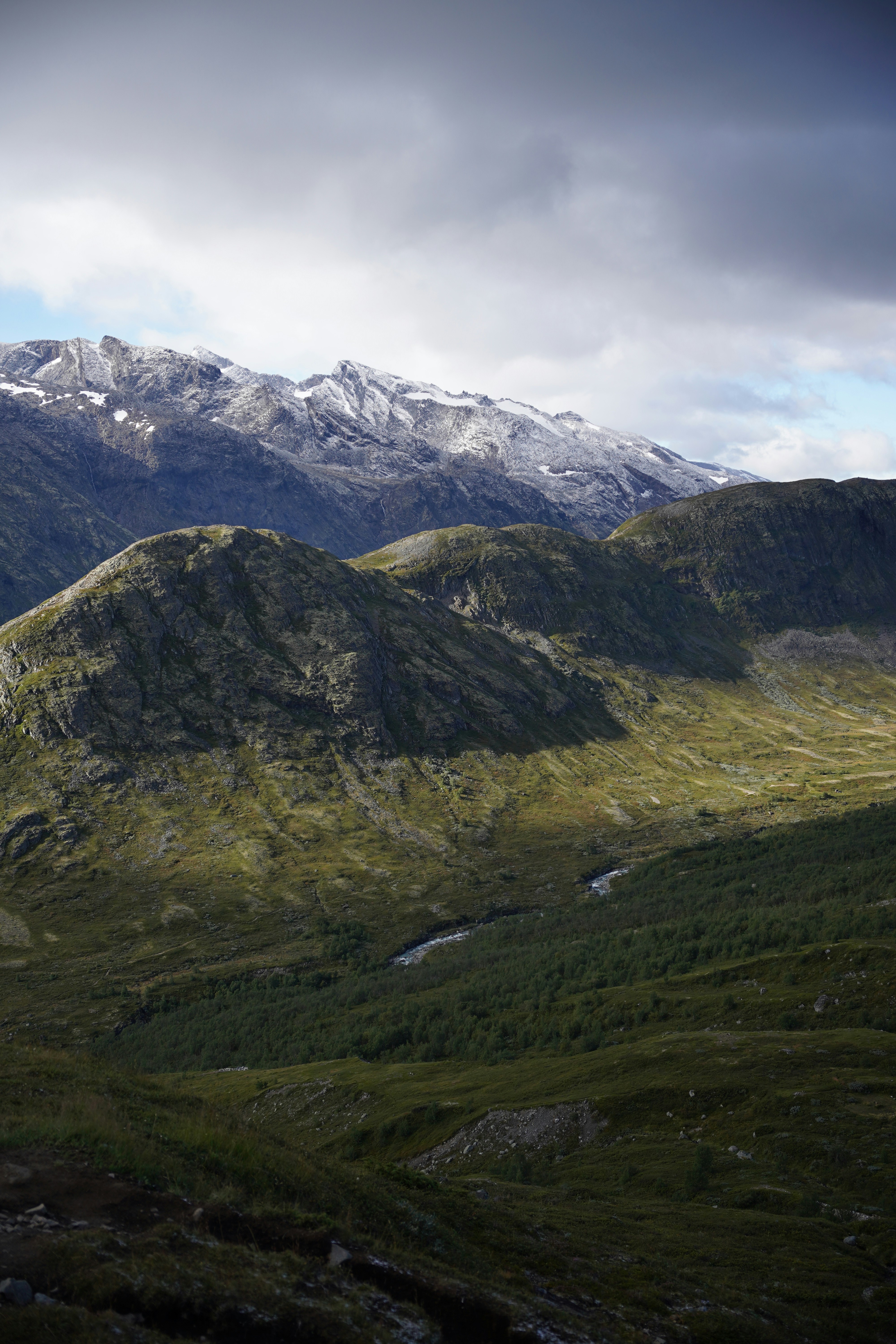 Sunlight over alpine ridges in Norway | Sunlit mountains and green valley with a river