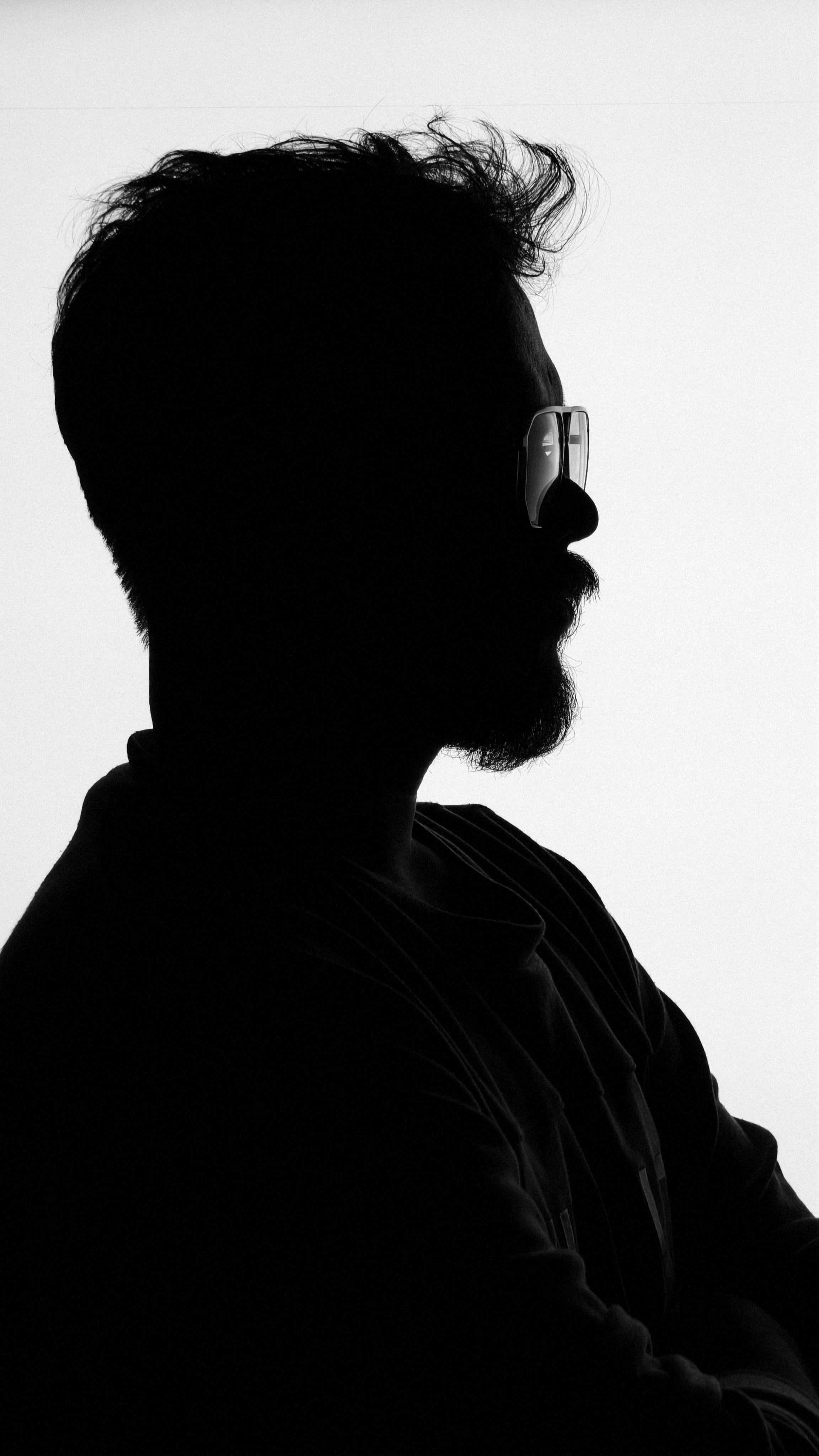 Silhouette of a man wearing glasses with a beard.