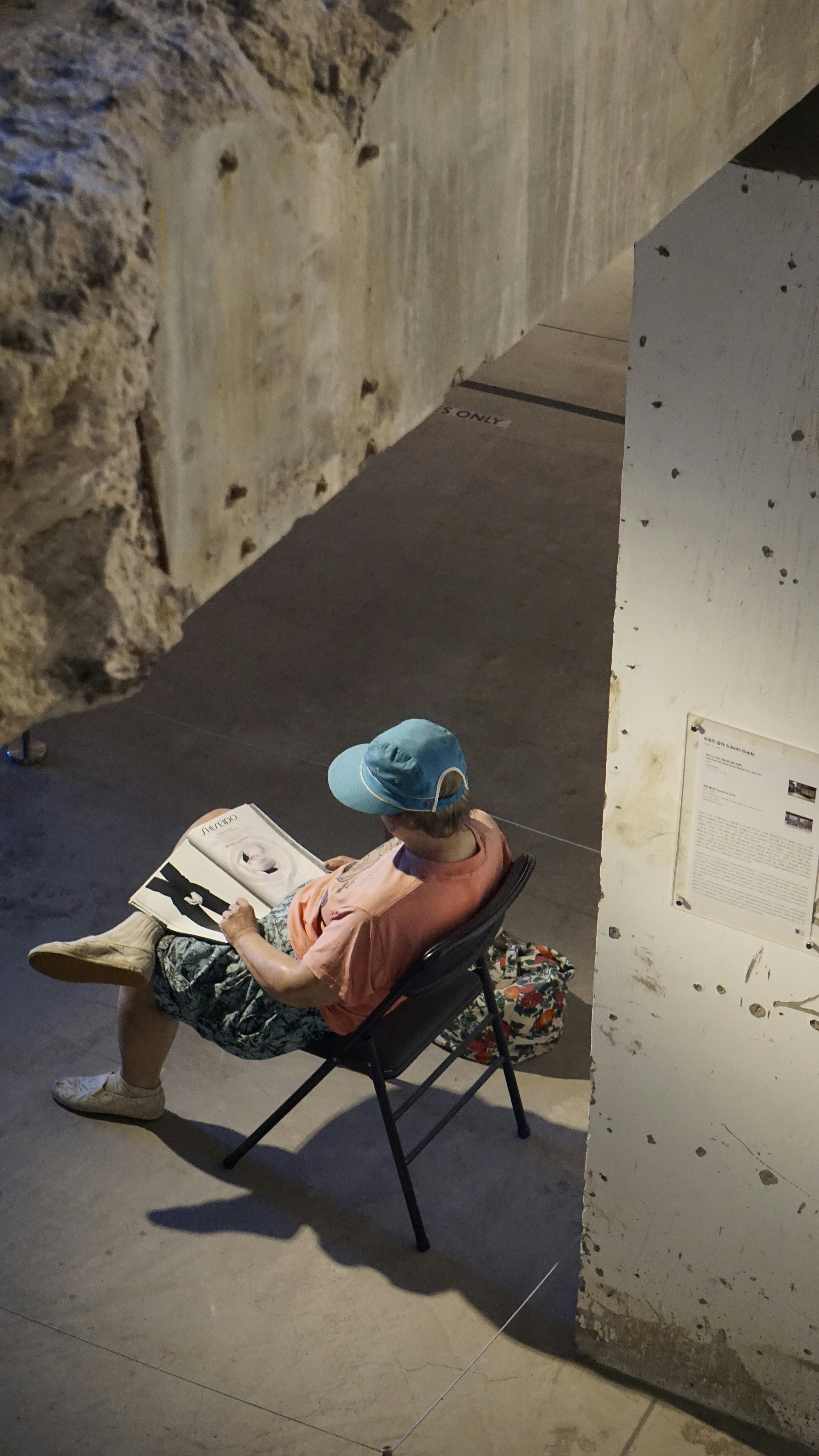 Person wearing a hat reads a book while sitting.