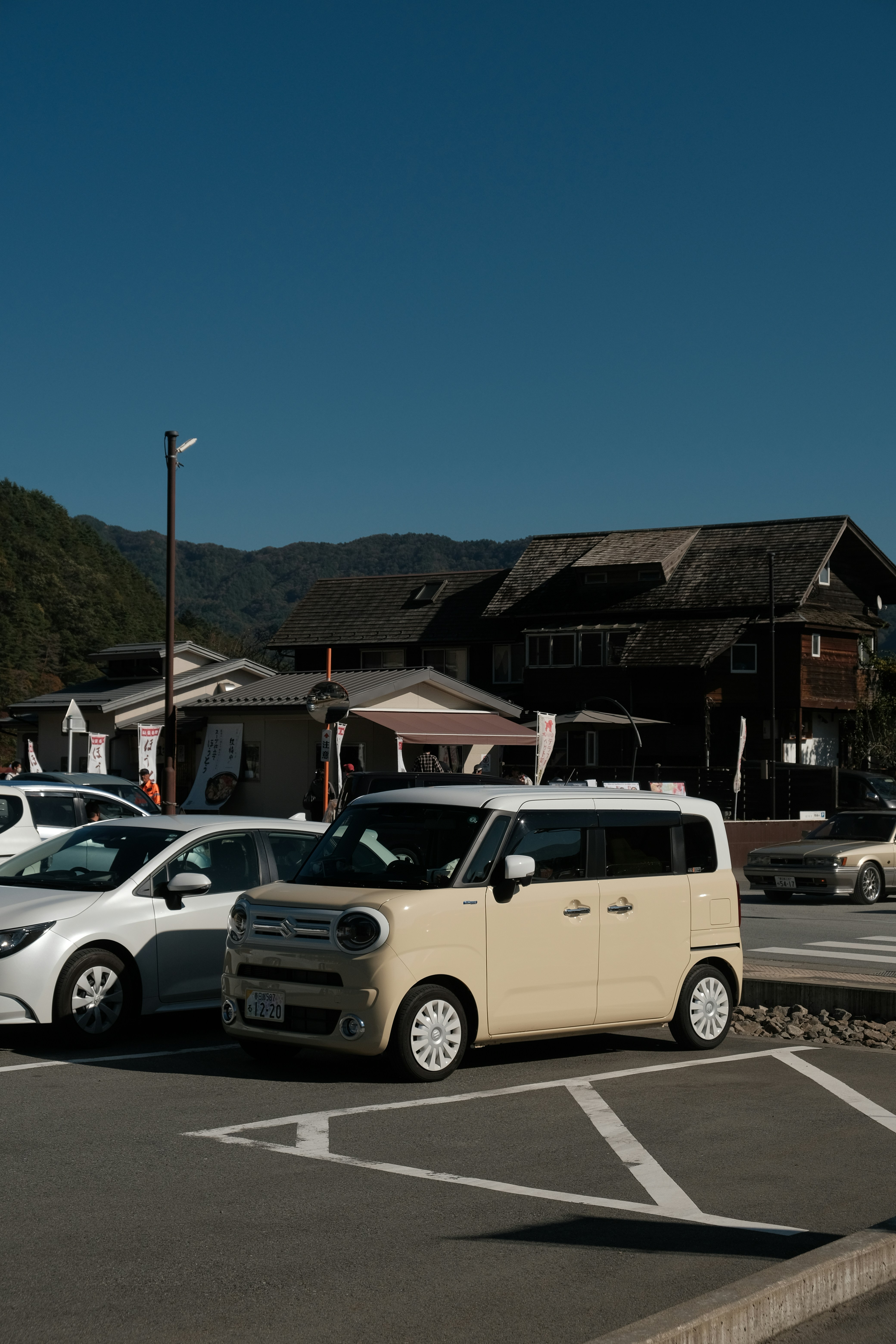 Several cars parked in a lot with buildings behind.