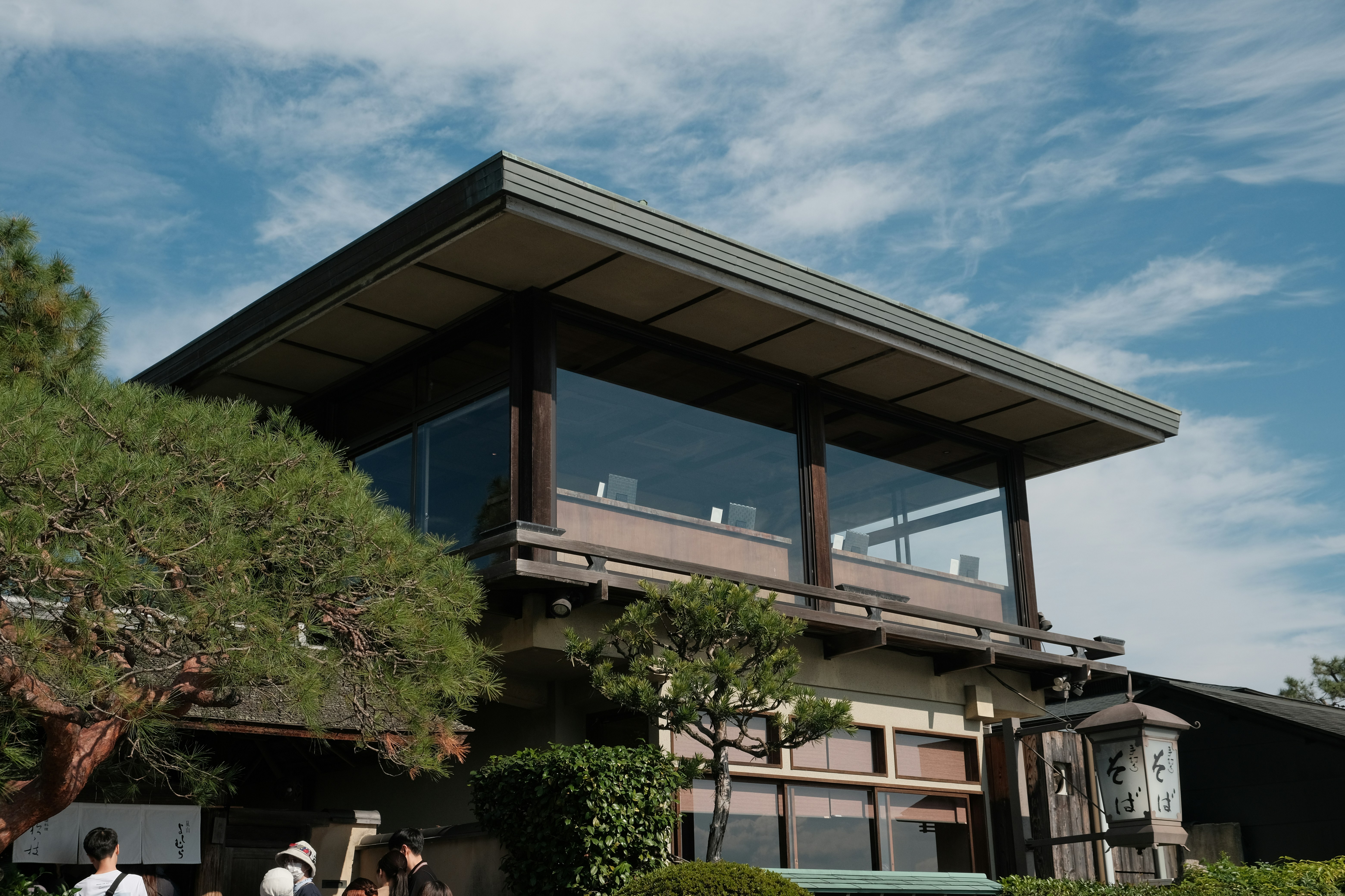 A contemporary building with large glass windows surrounded by lush greenery, showcasing a blend of modern architecture and natural elements.