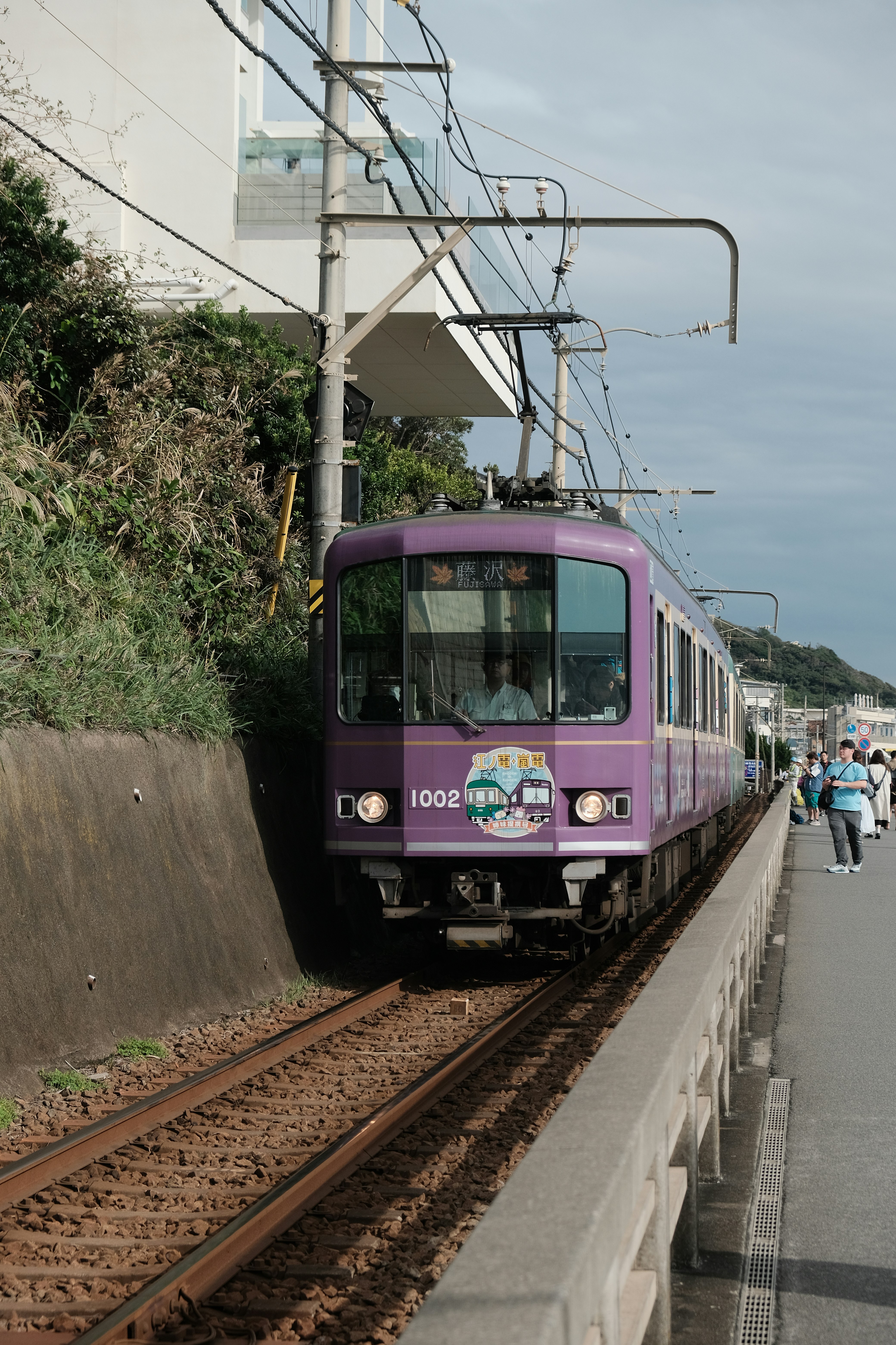 A purple train approaches on a sunny day.