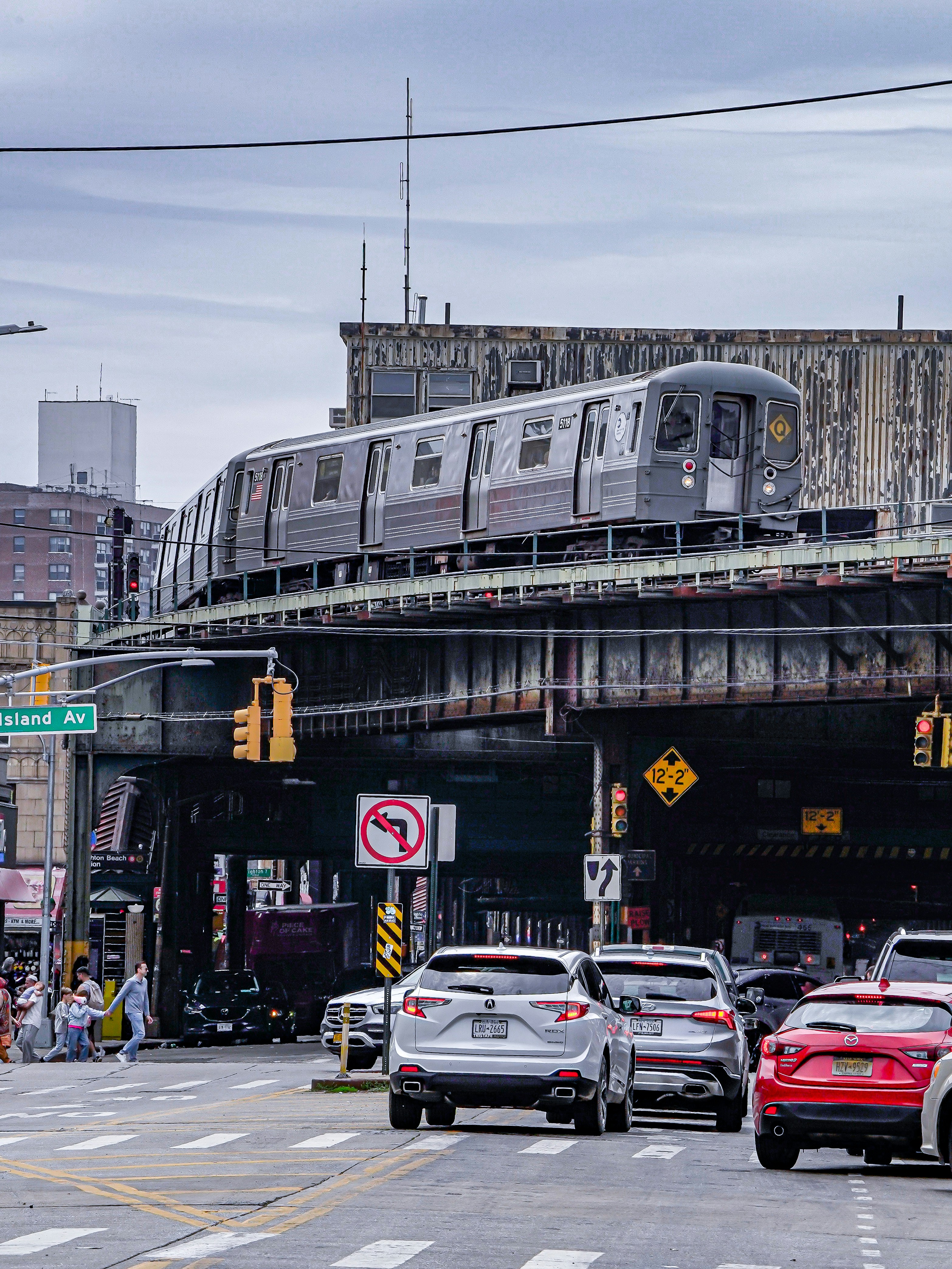 Quest For Perfection - SMNYCMan | Elevated train passes over busy city street with cars.