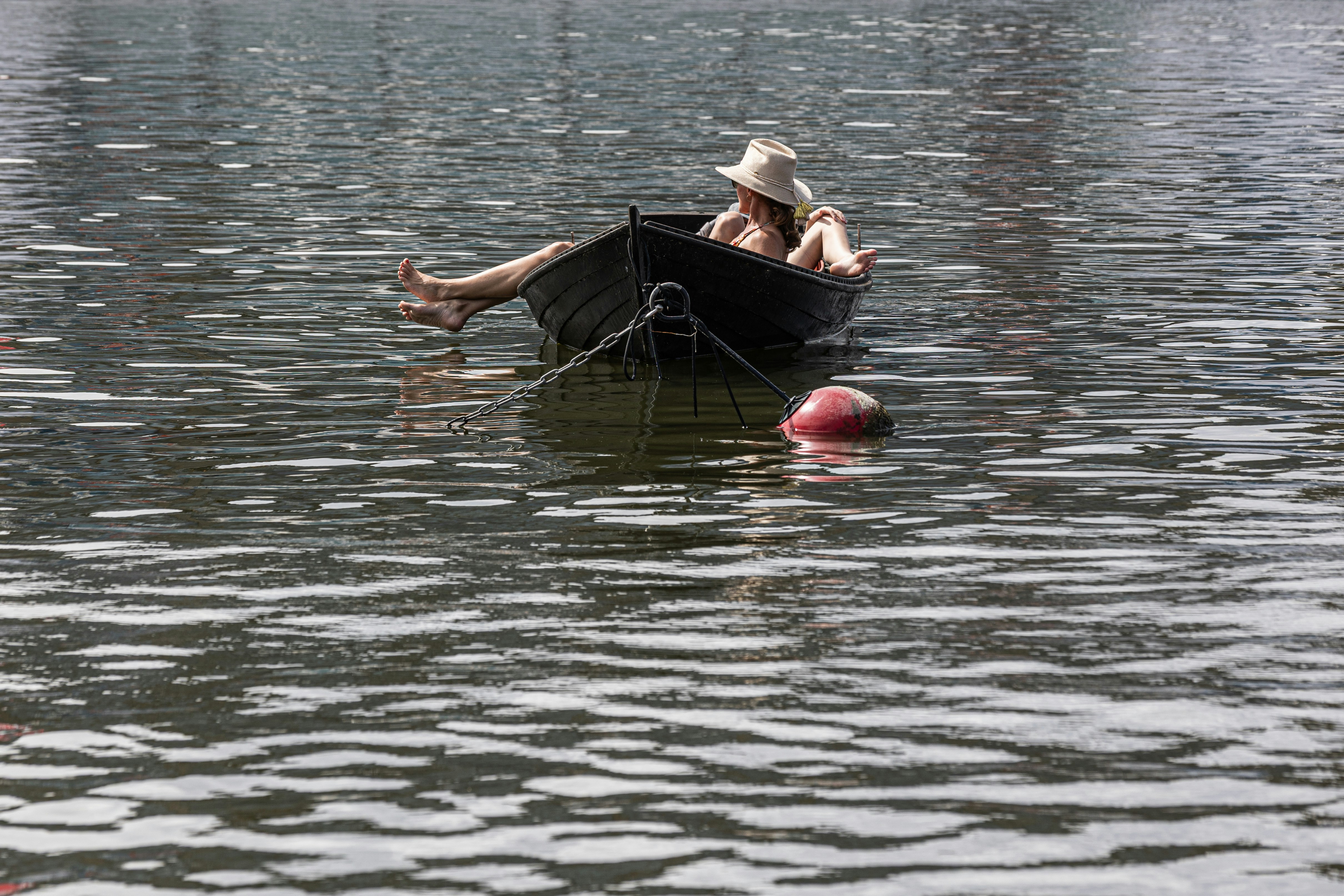 Person relaxing in a small boat on the water.