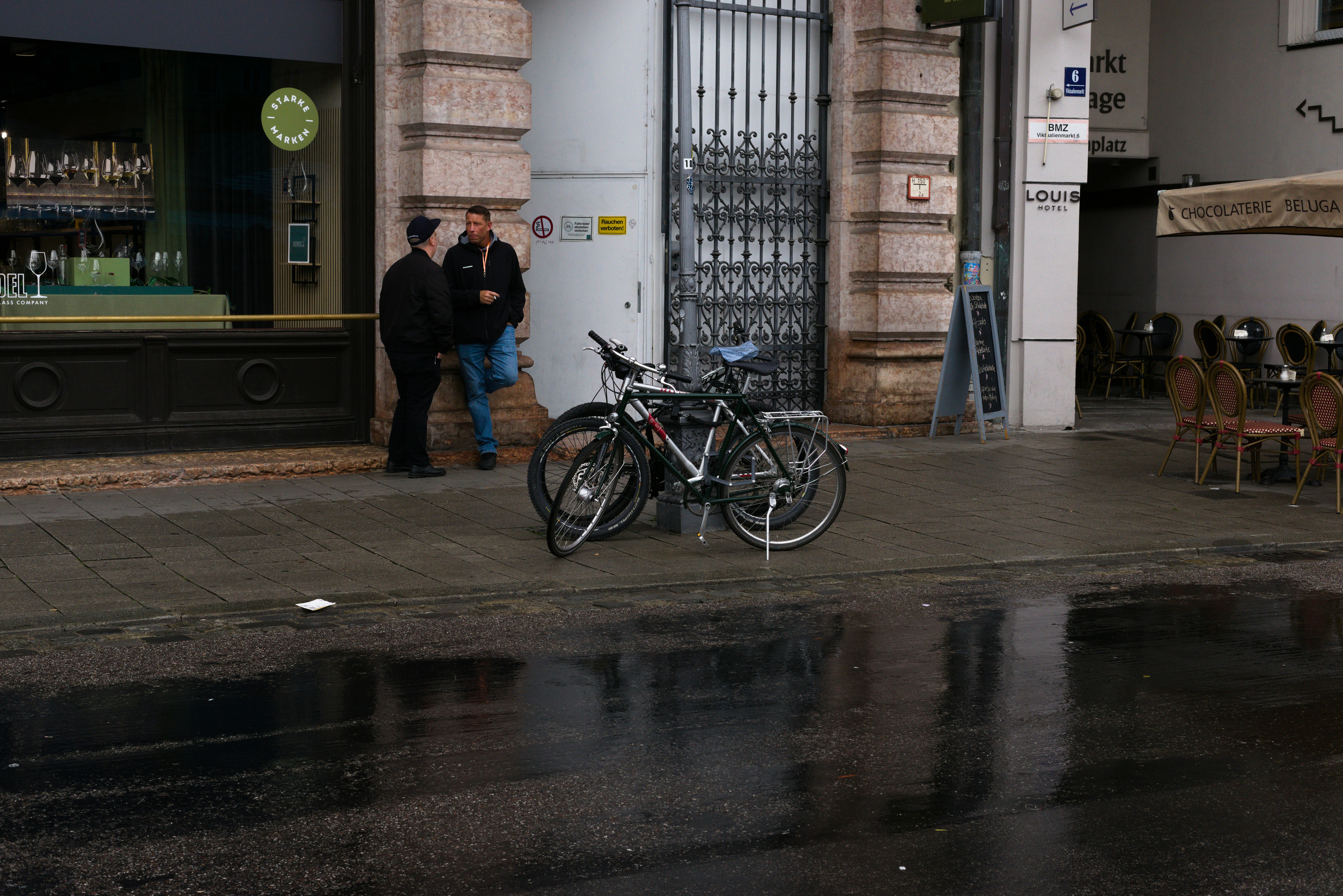 Curbside Conversation by Bicycle Row on a Damp City Street
