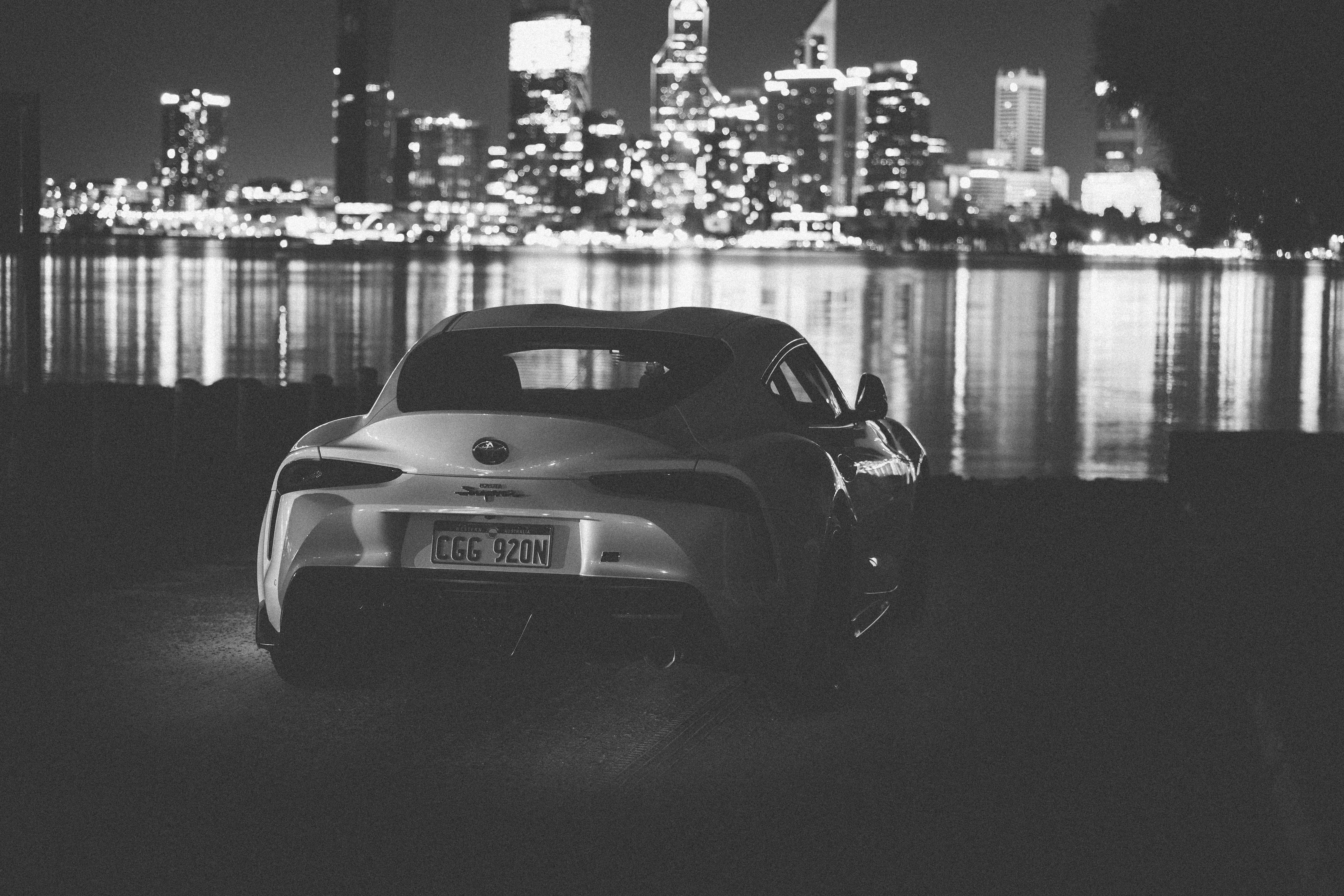 Harbor Reverie: A Night-Parked Sports Car Against a City Light Horizon