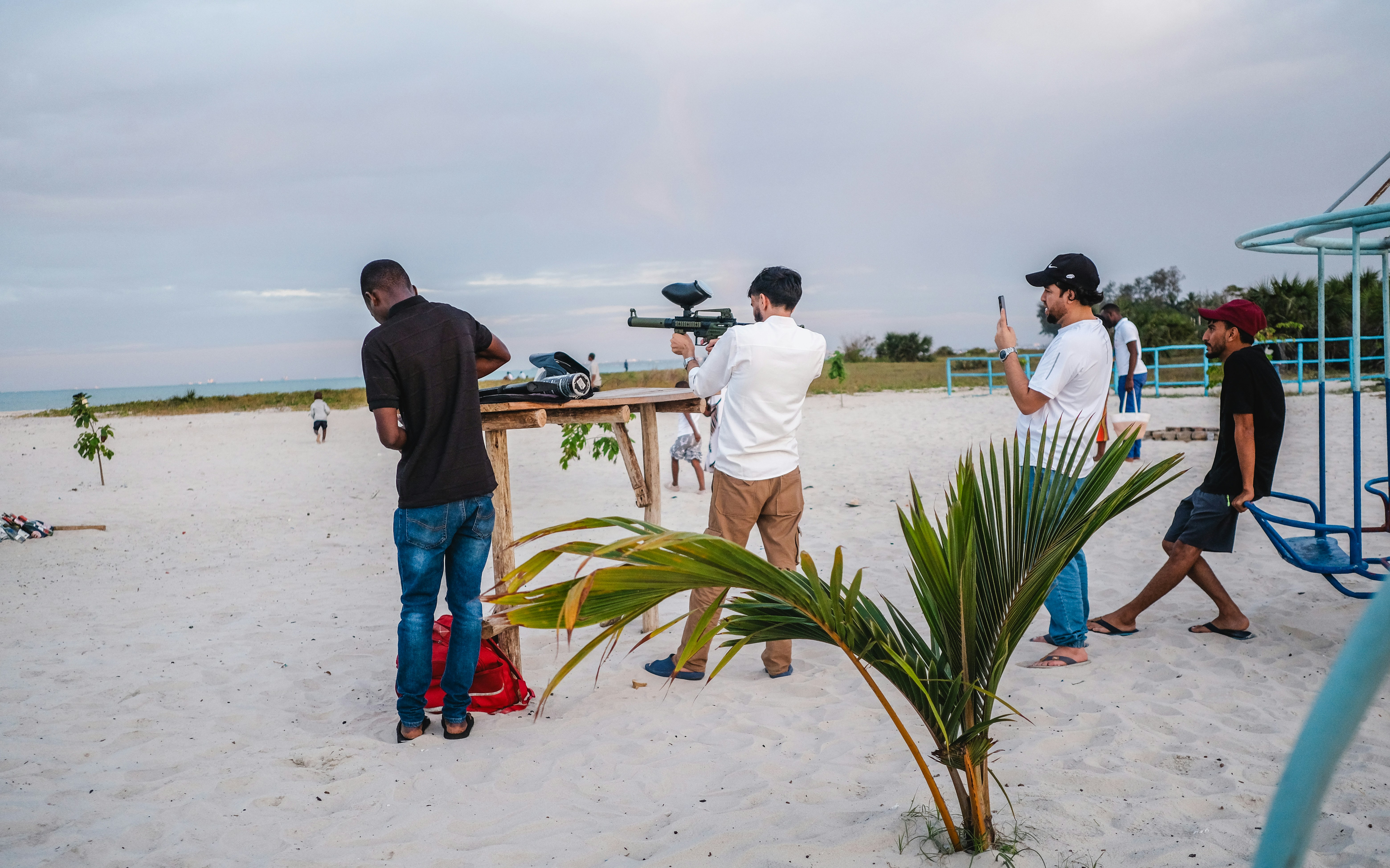 Dar es Salaam • September, 2025 | People on a beach with a car and playground equipment.