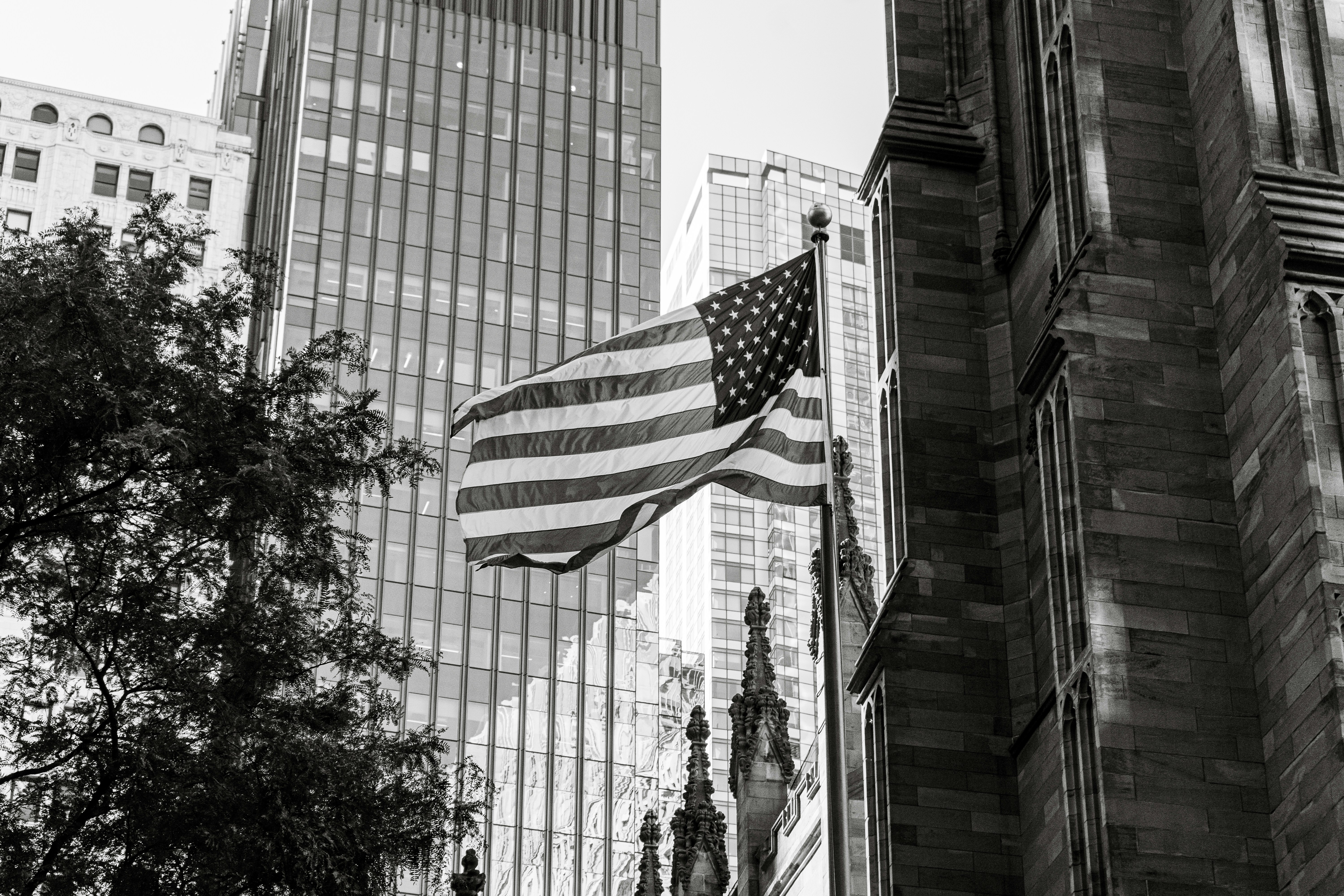 American flag waves near tall buildings in city.