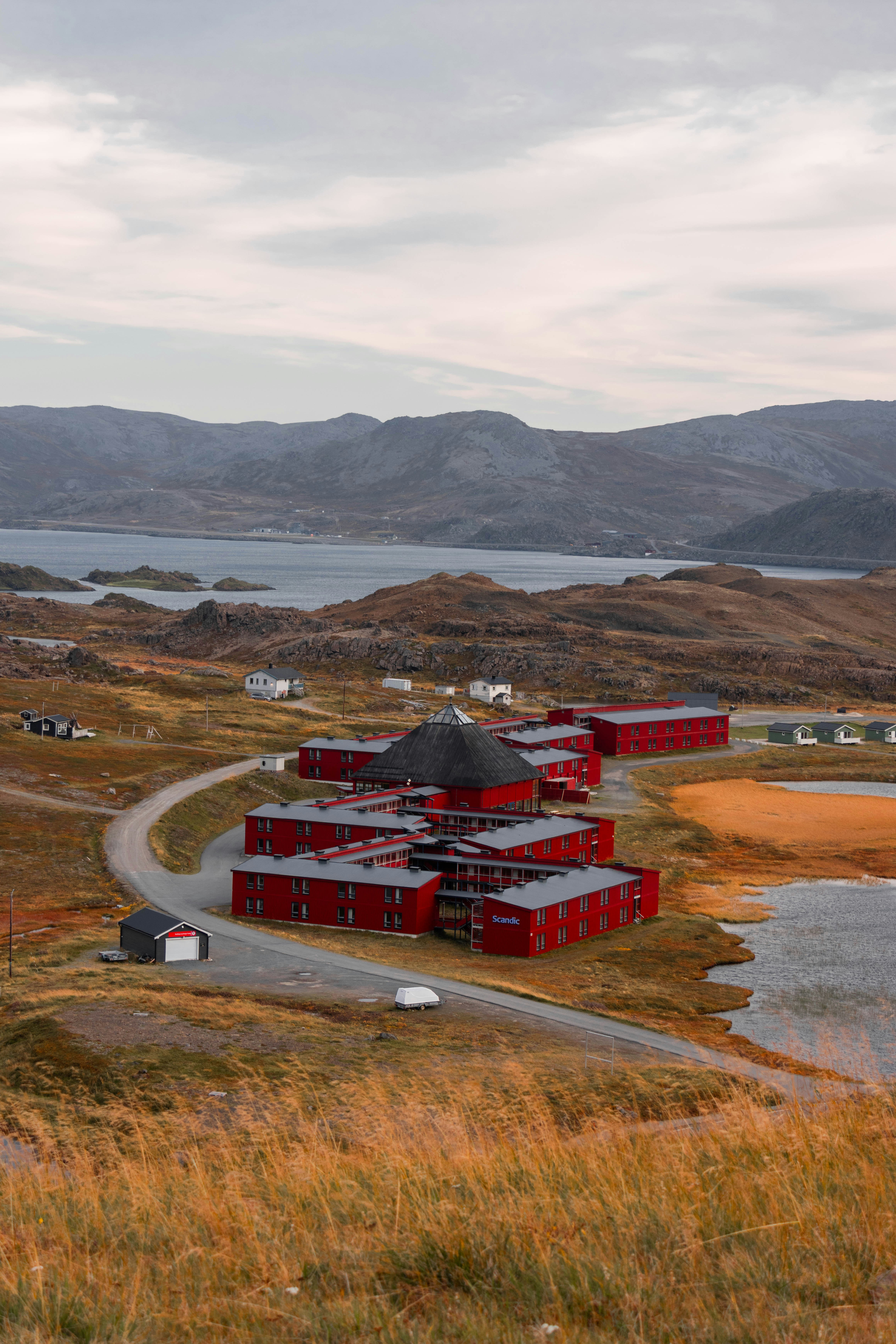 Red buildings in a remote, rocky landscape with water. photo – Free ...