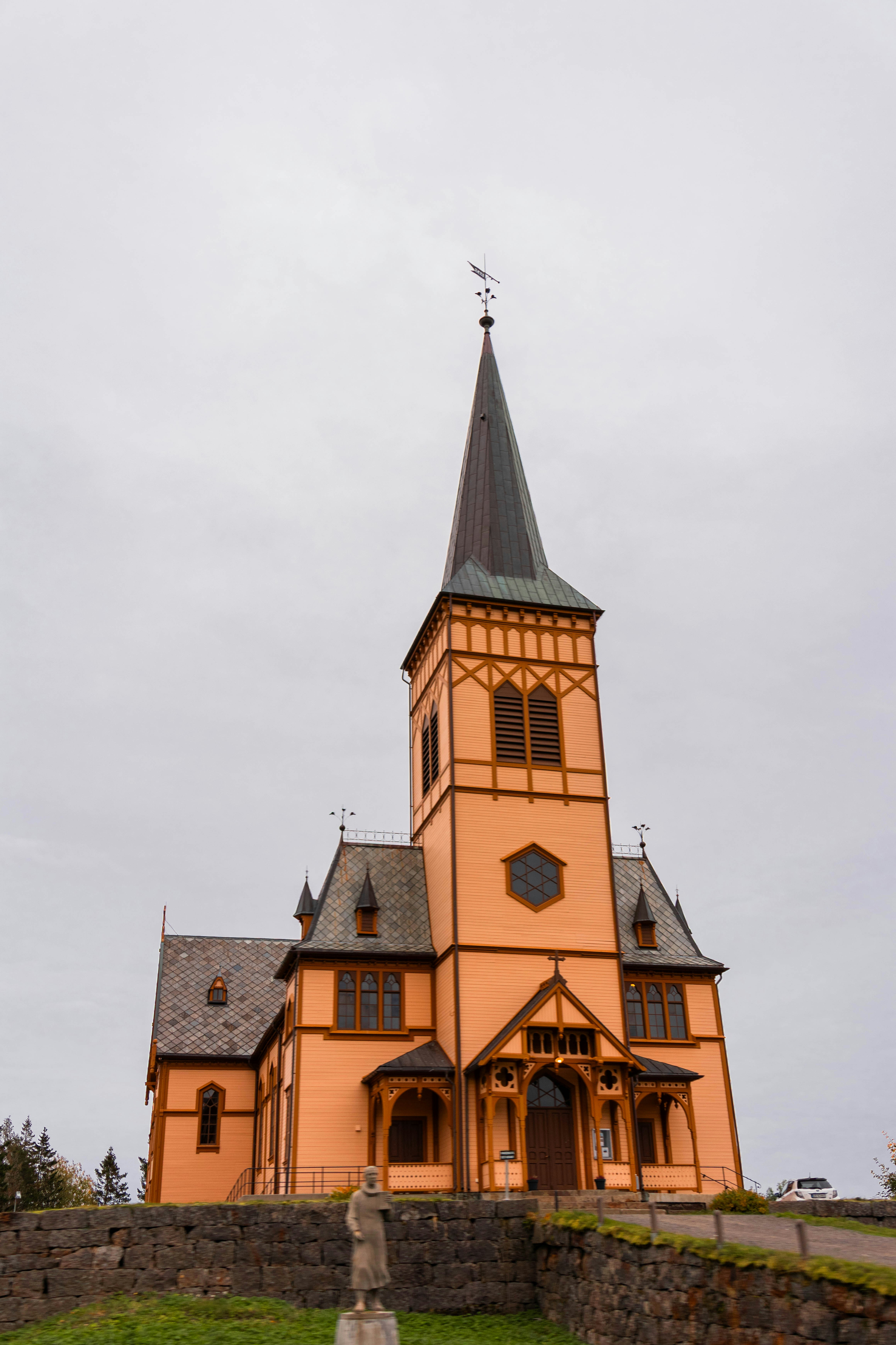Orange church with a tall steeple under cloudy sky