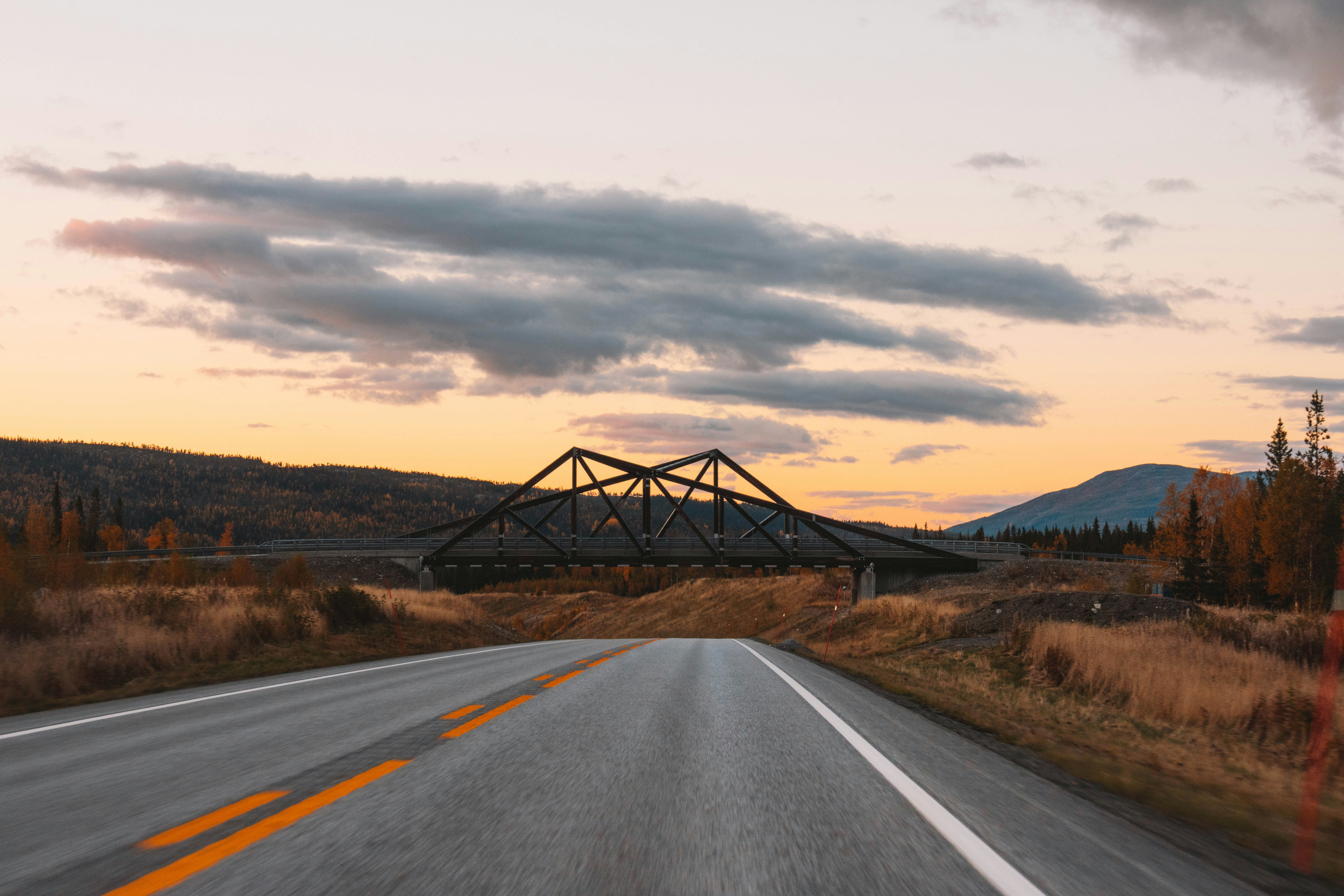 A road leads to a bridge at sunset.
