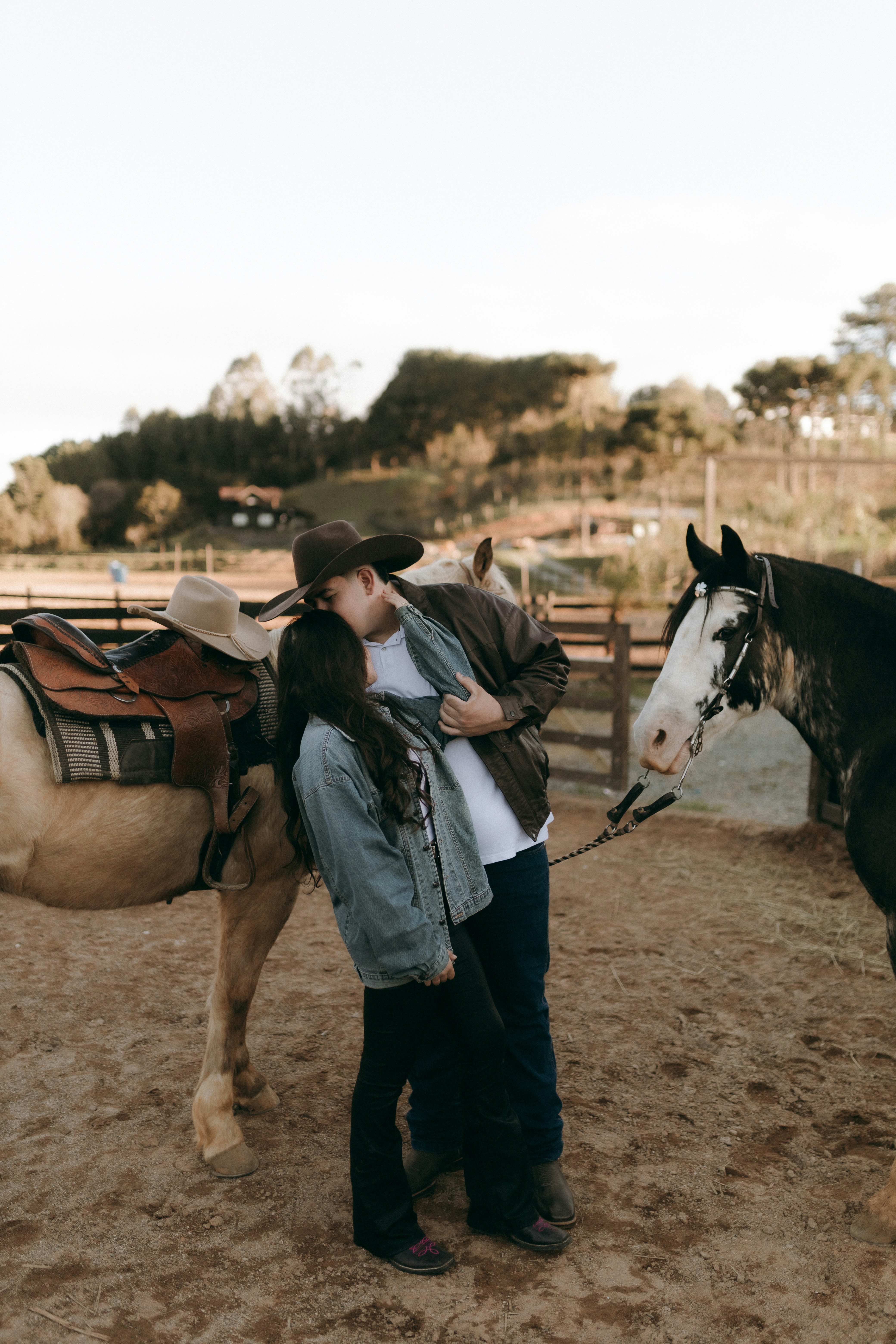Couple kissing by horses on a ranch