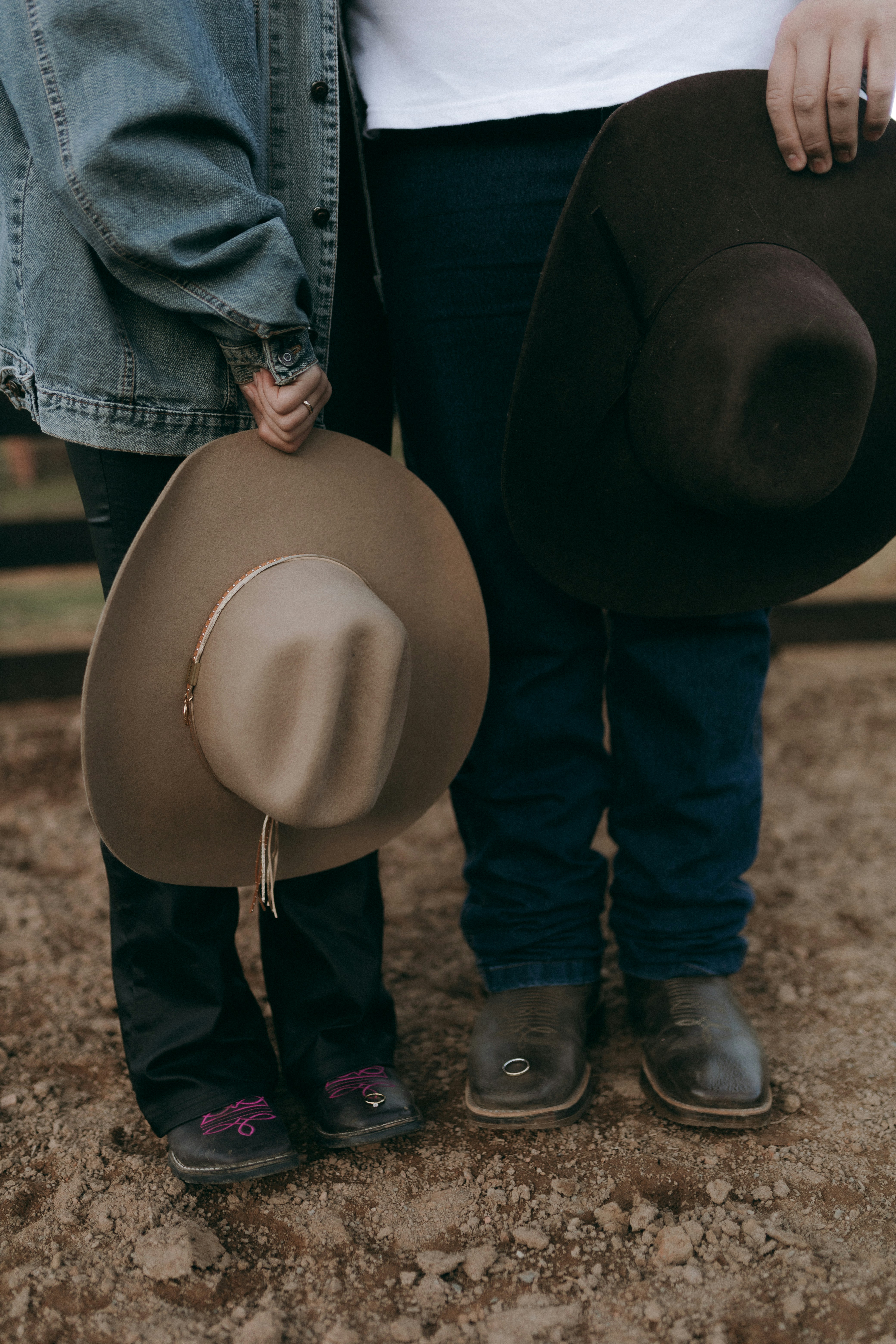 Two people holding cowboy hats and wearing boots