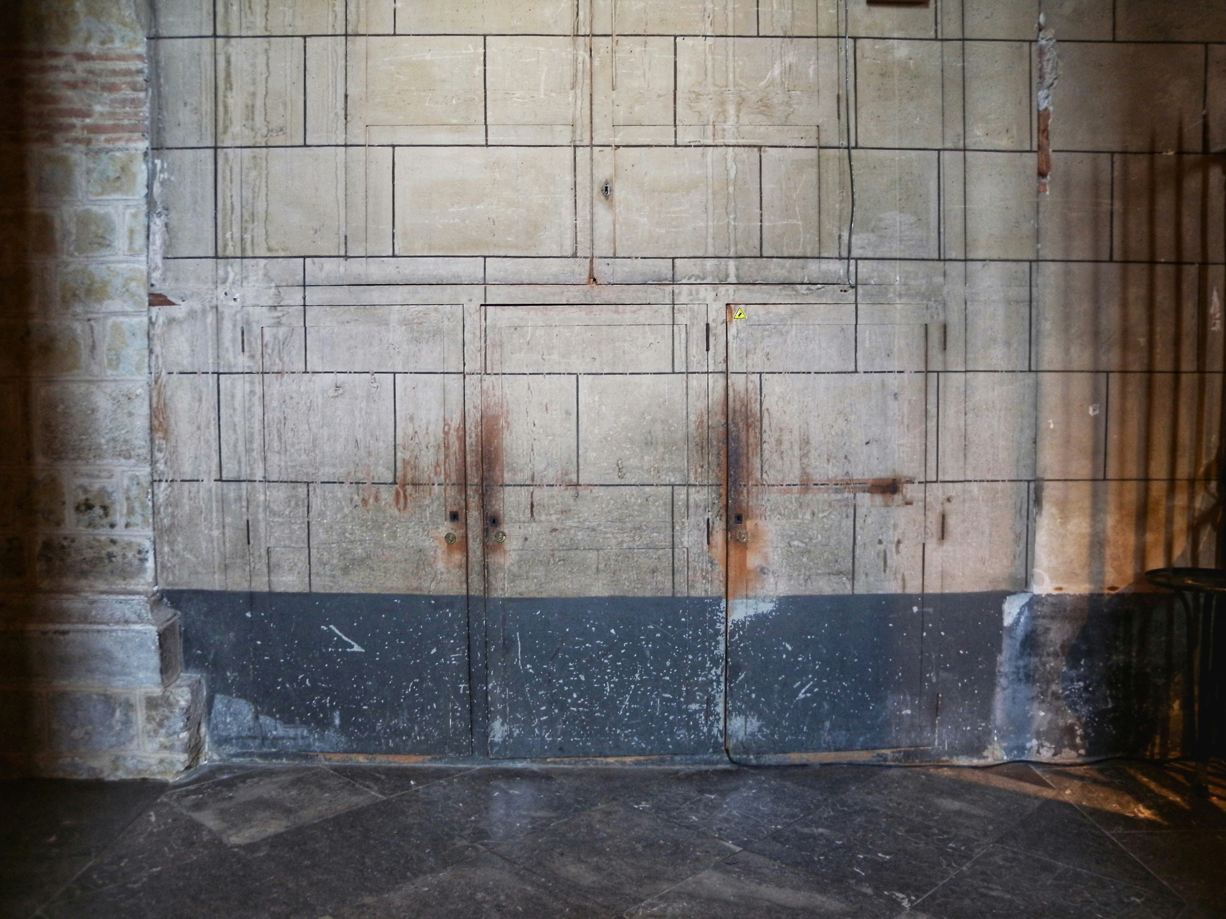 A weathered tiled wall with a dark base