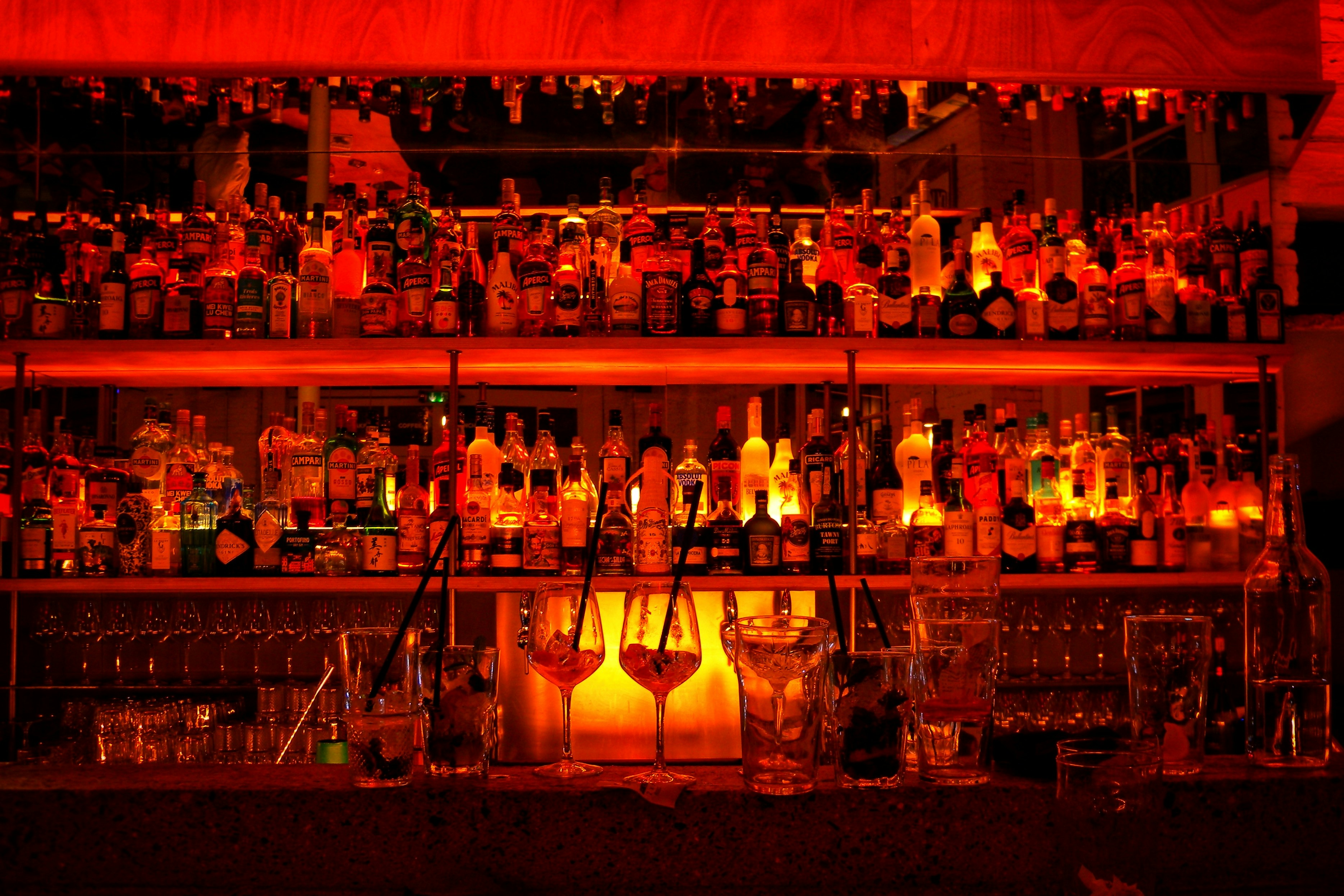 Shelves of liquor bottles illuminated by red light