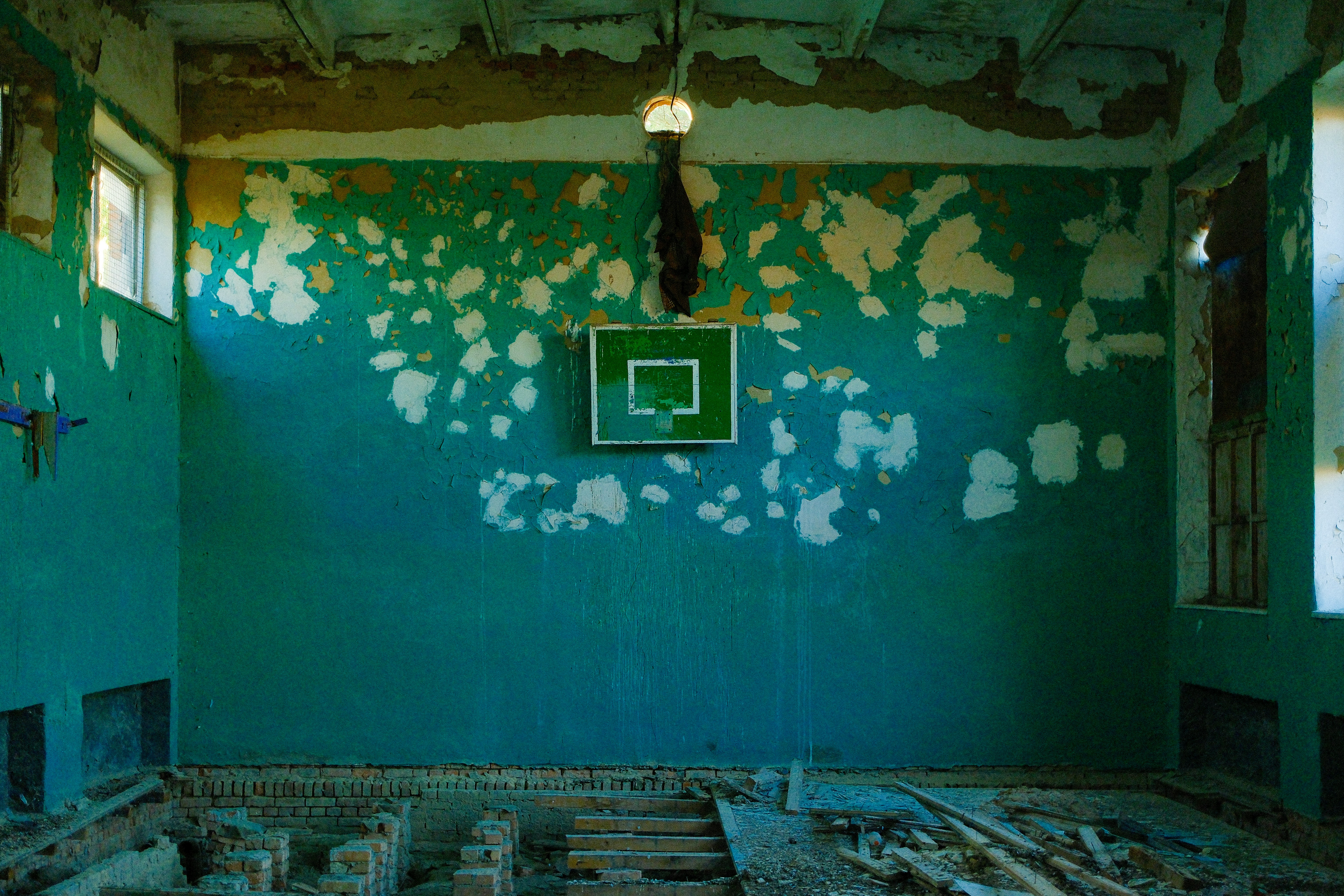 Peeling paint on a teal wall in an abandoned room.
