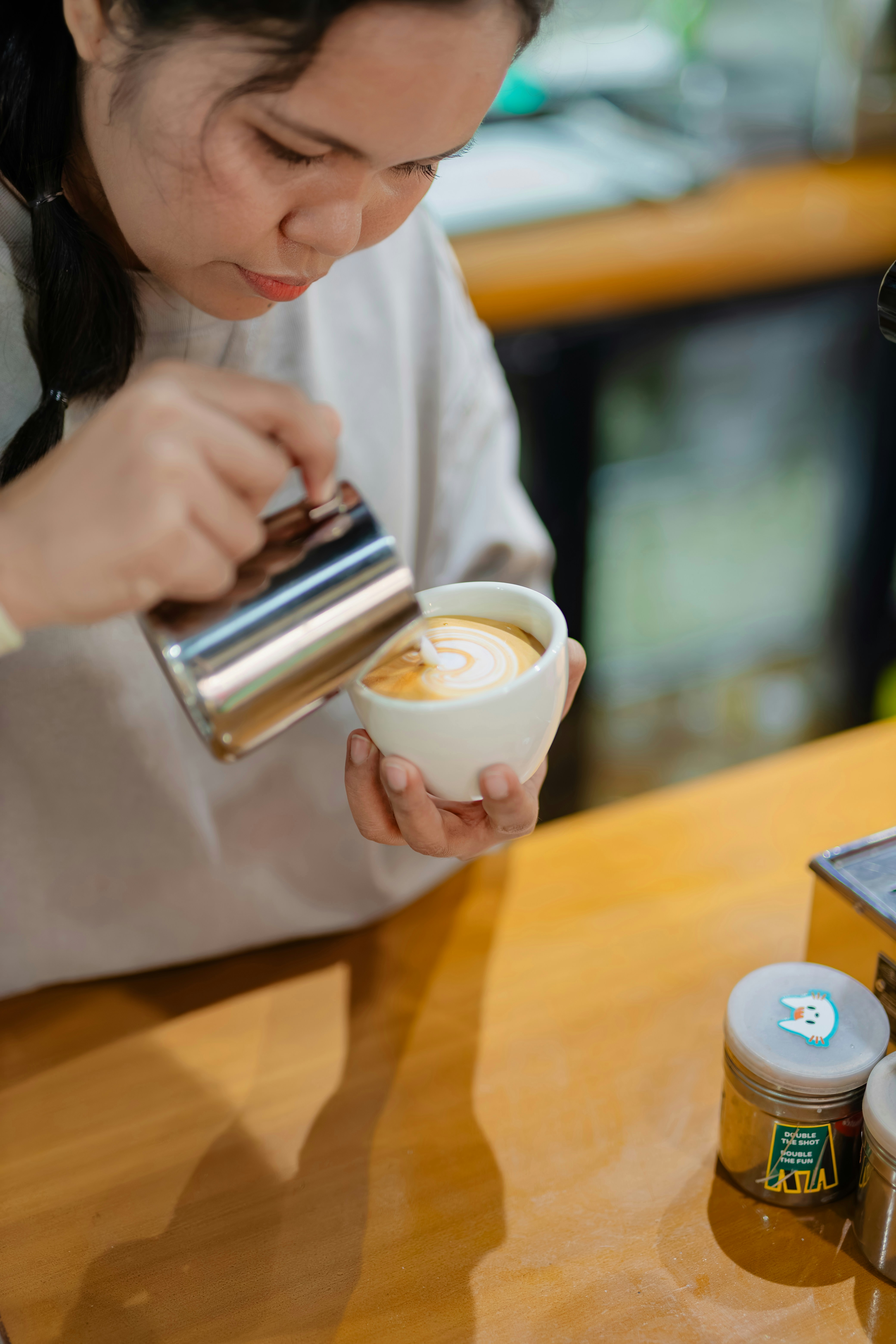 Barista pouring latte art into a coffee cup