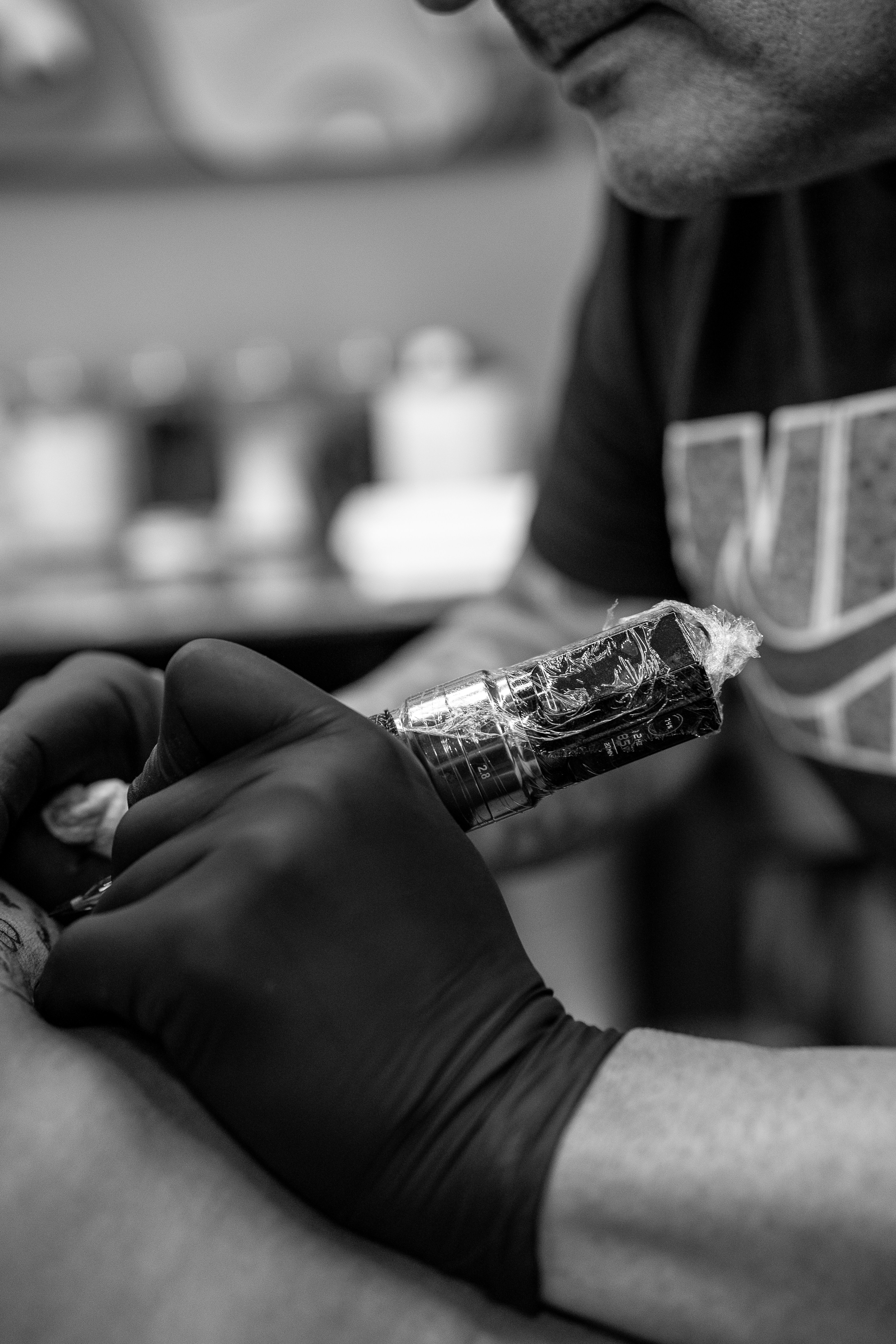 Black and White Tattoo Gun | Tattoo artist working on client with black gloves.