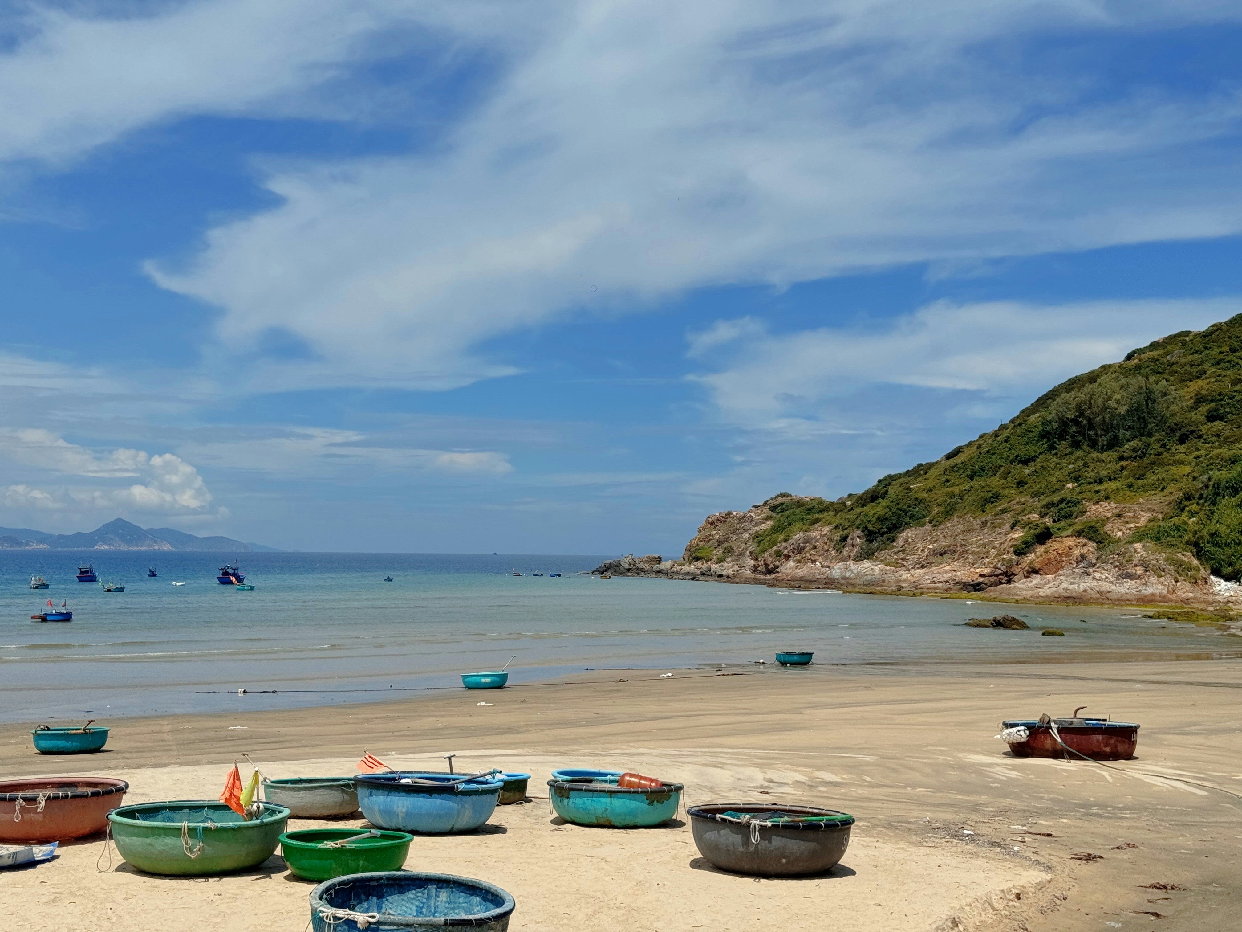 Round fishing boats on a sandy beach with ocean background