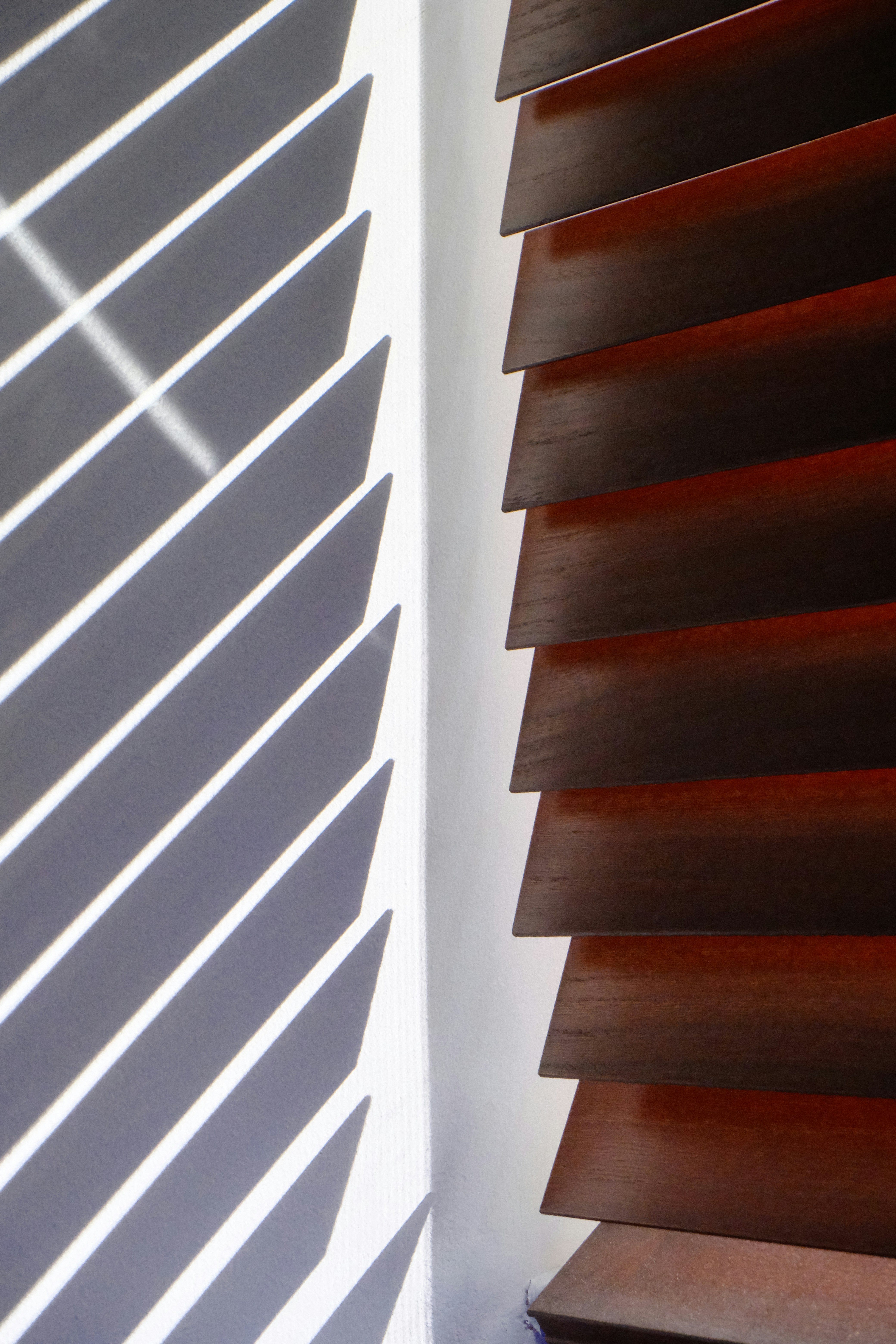 Wooden blinds casting striped shadows on wall