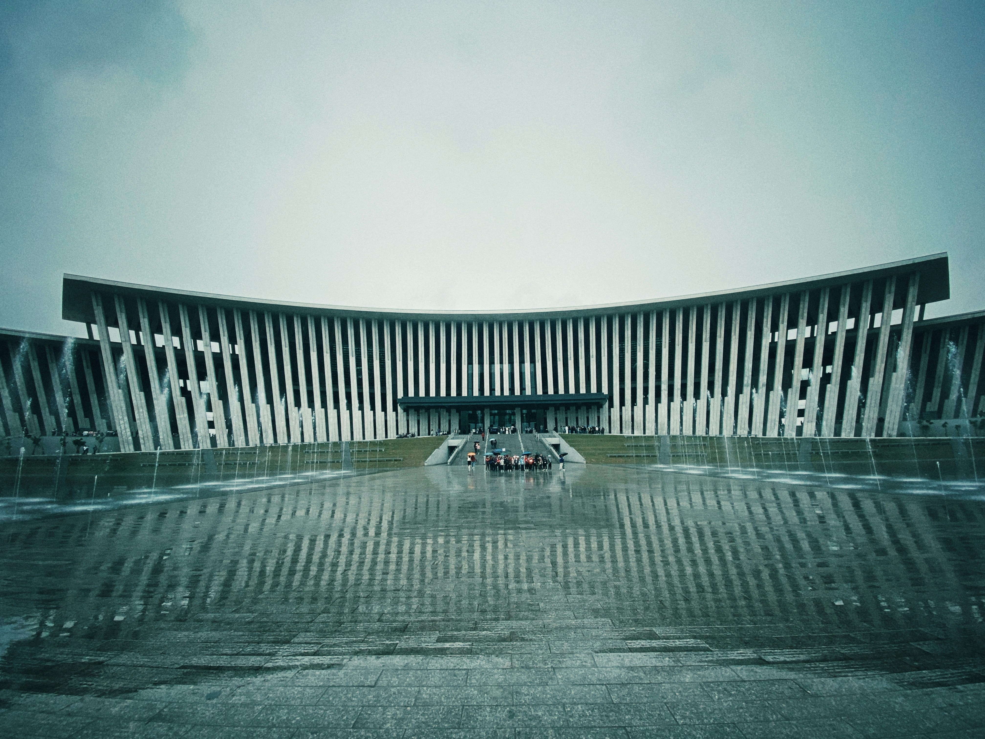 A striking modern architectural structure with vertical lines reflecting in a water feature, creating a harmonious visual balance.