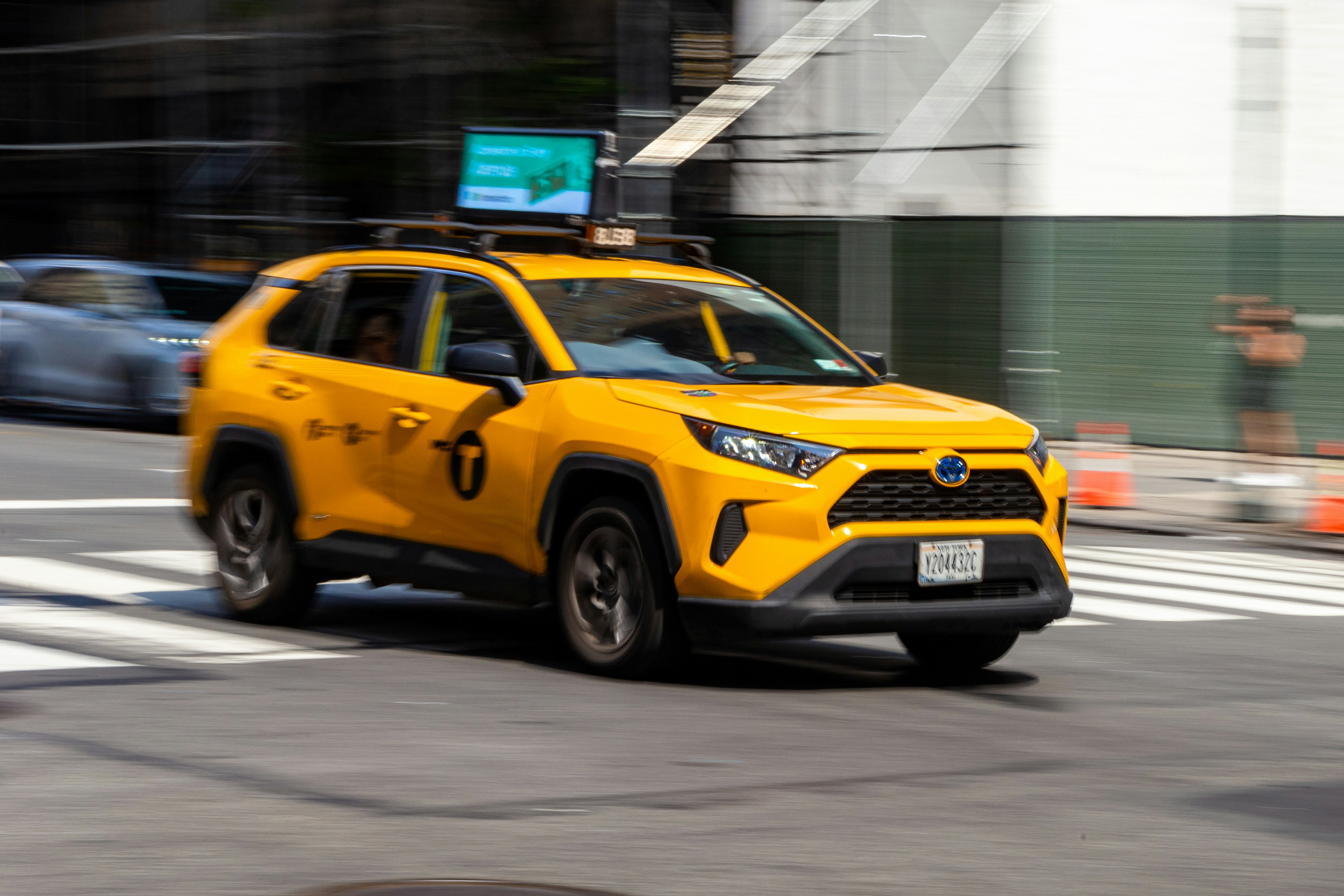 A yellow taxi navigating a city intersection, showcasing the dynamic energy of urban life.