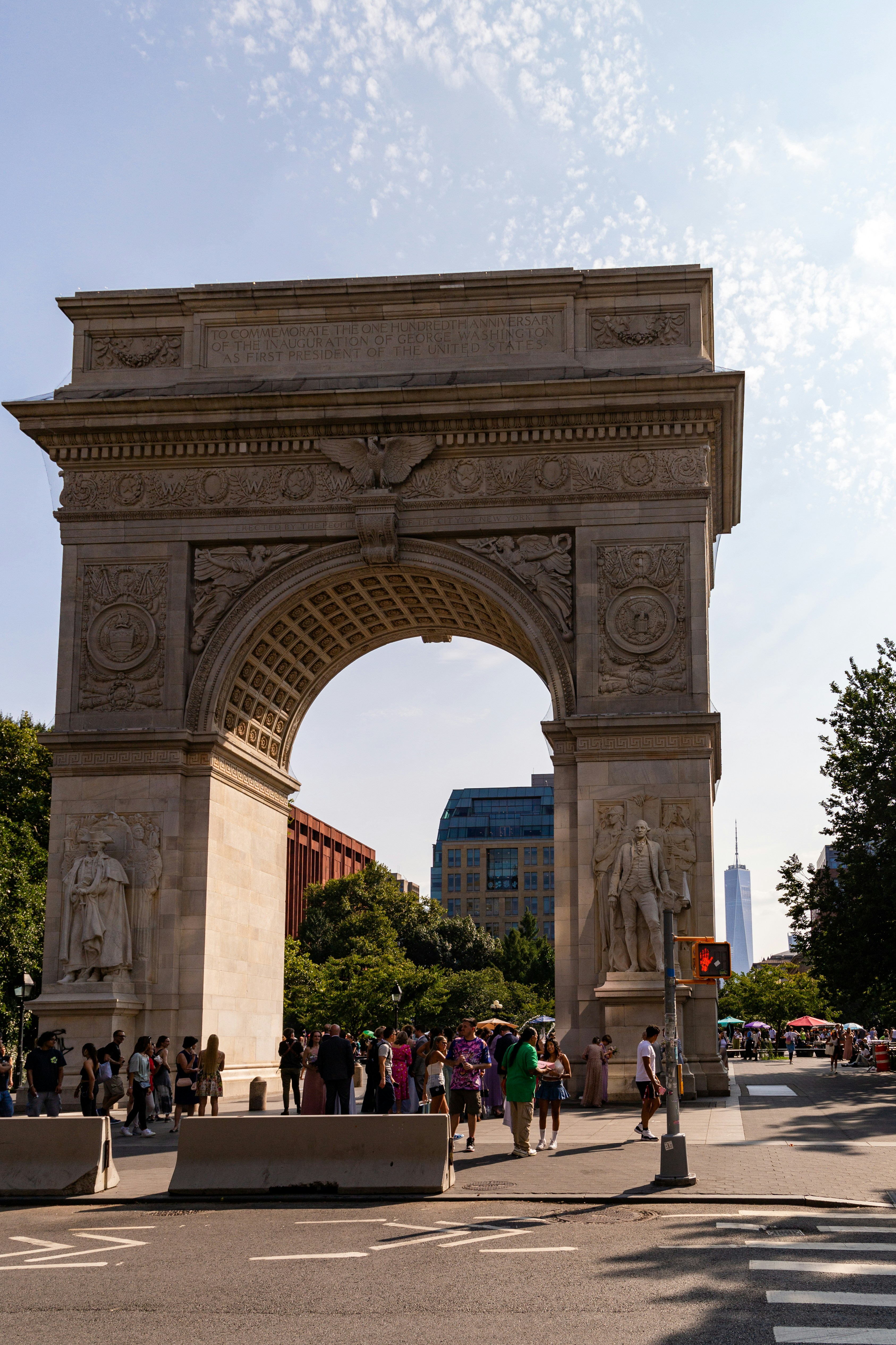 The iconic Washington Square Arch stands tall amidst a bustling crowd, with modern skyscrapers peeking through the archway. The scene captures the blend of historical and contemporary architecture.