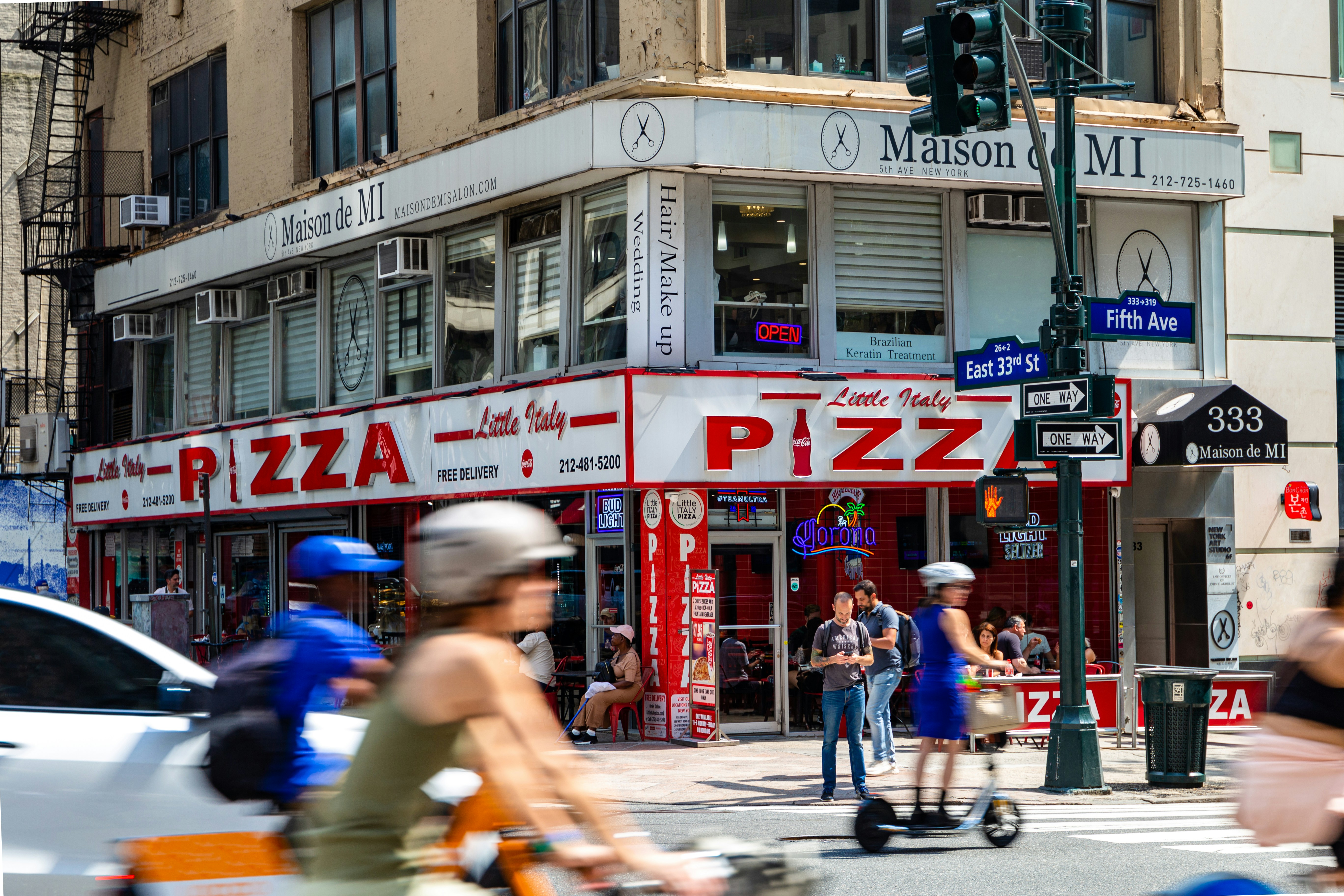 A busy street corner with a pizza restaurant.