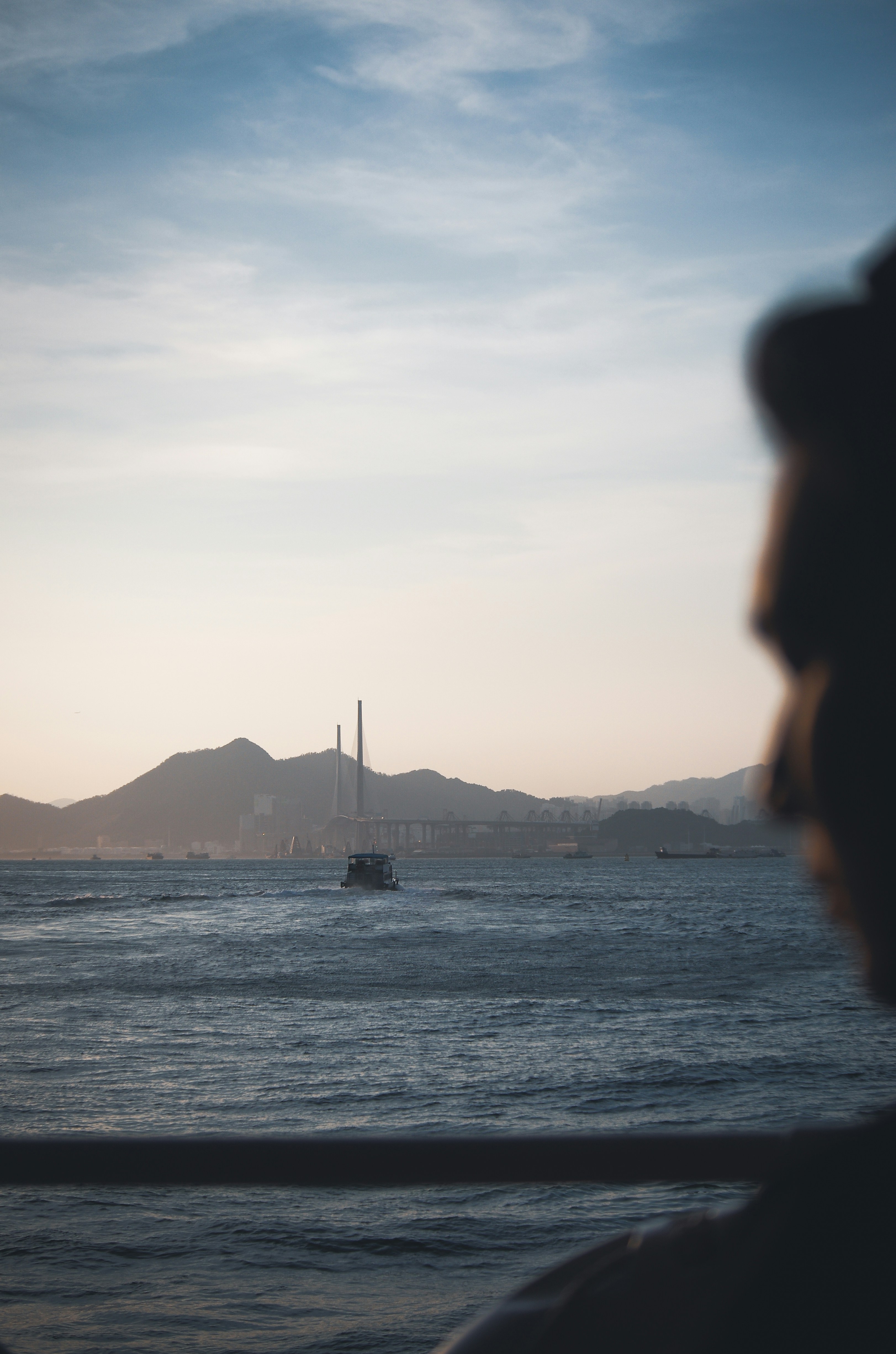 Horizon Quiet: A Lone Boat Traverses a Bay Under a Distant Bridge at Sunset